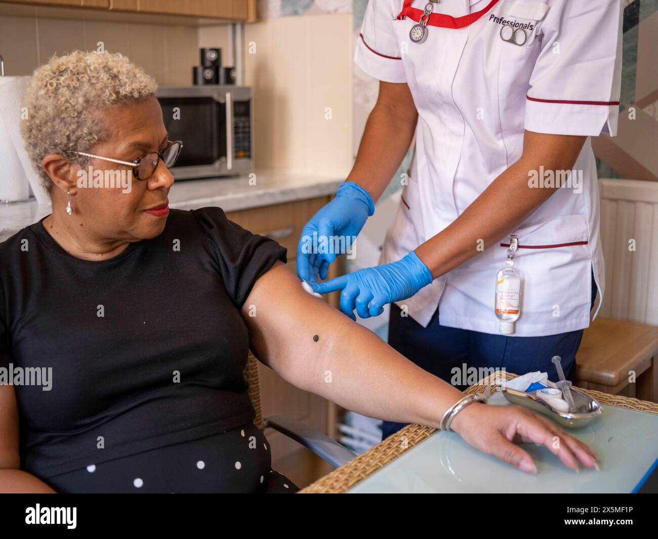 Nurse visiting mature woman at her house, preparing injection Stock ...