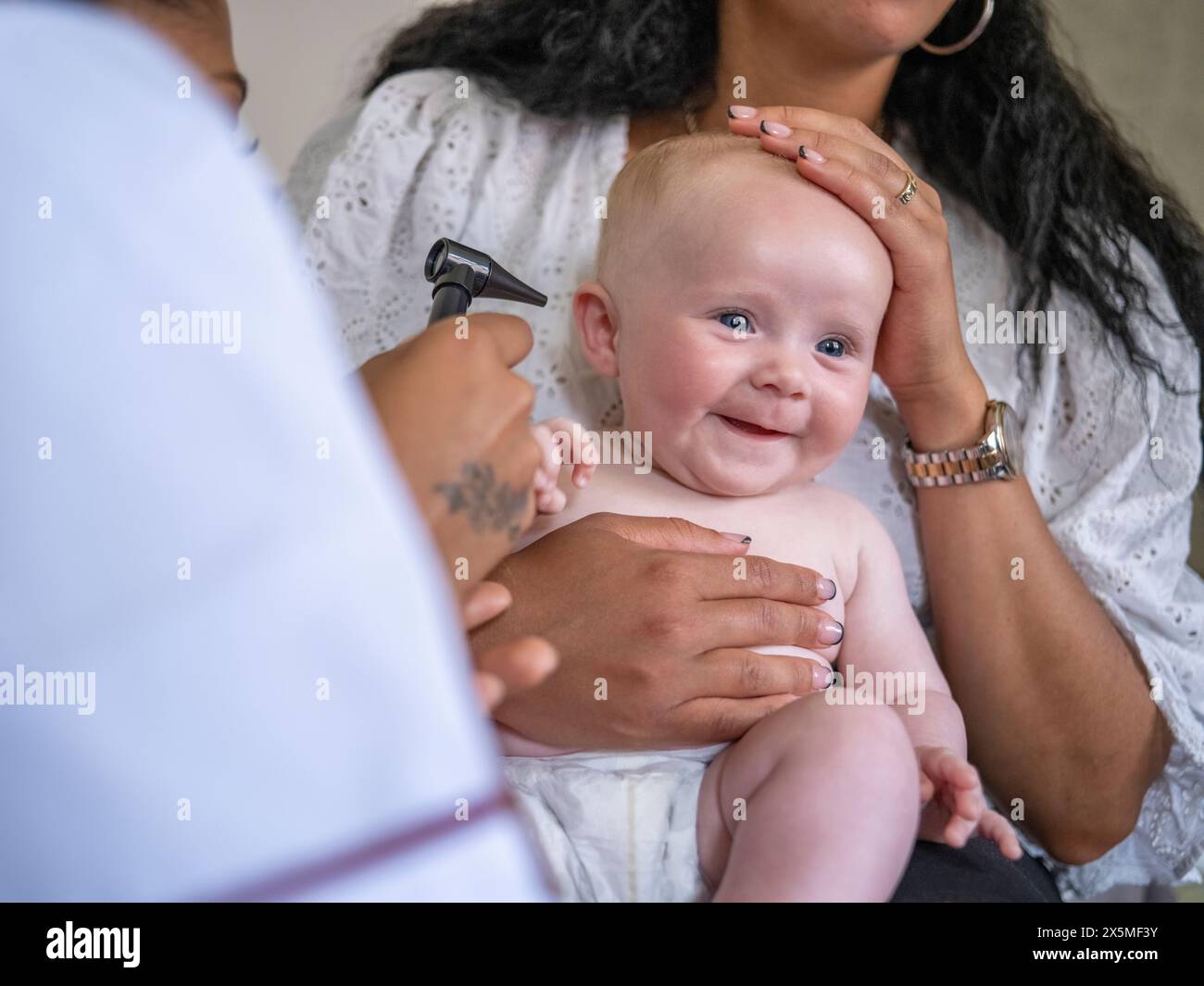 Nurse examining baby girl (2-5 months) with otoscope Stock Photo - Alamy