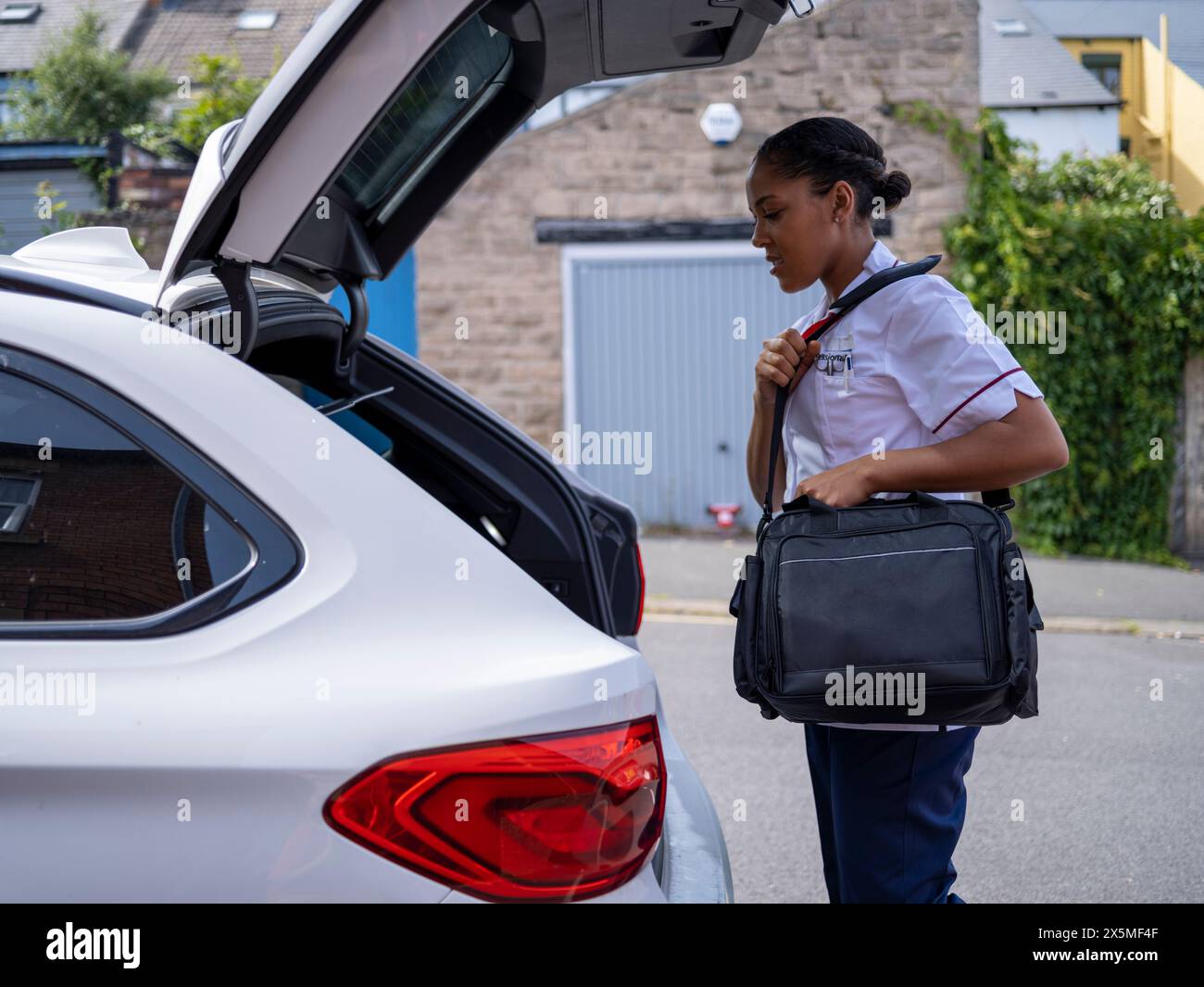 Nurse preparing to drive car, opening trunk Stock Photo - Alamy