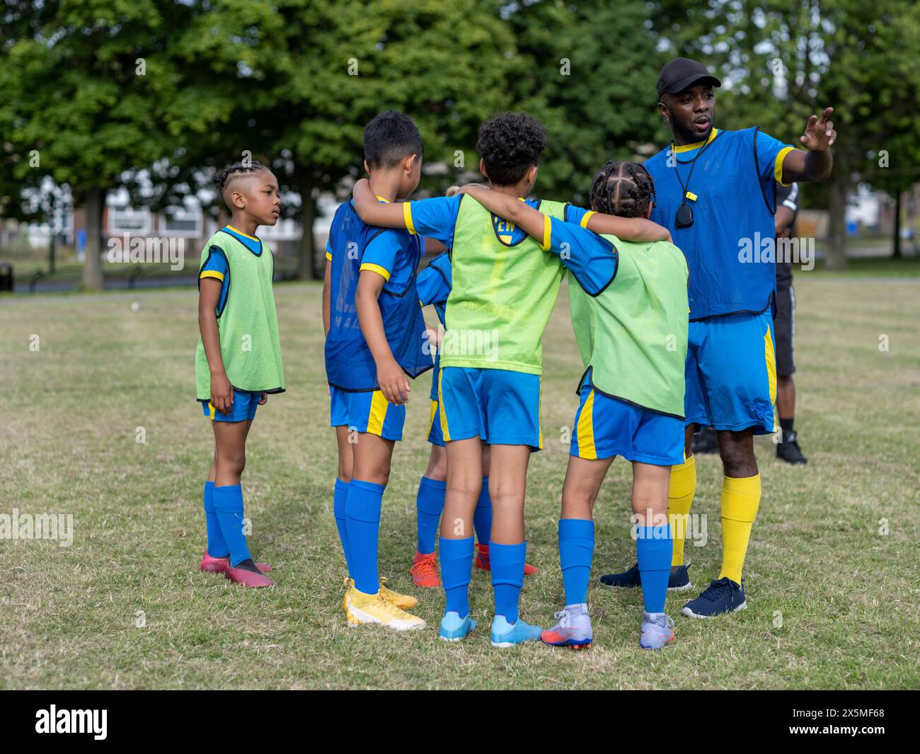 Coach giving instructions to kids (8-9) on soccer field Stock Photo - Alamy