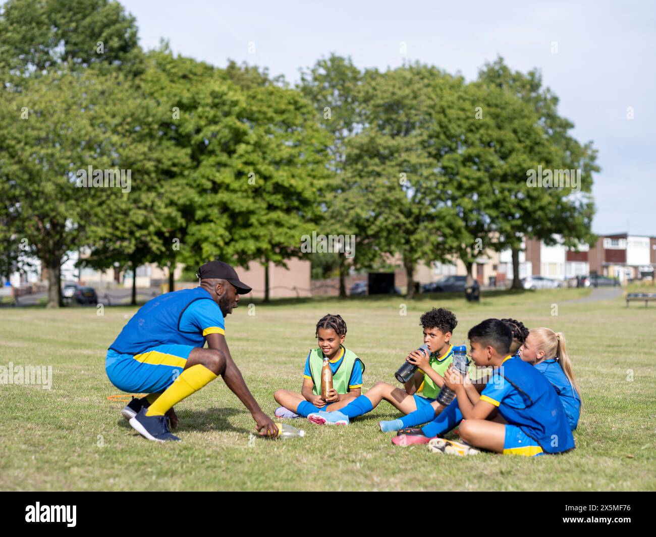 Coach giving instructions to kids (8-9) on soccer field Stock Photo - Alamy