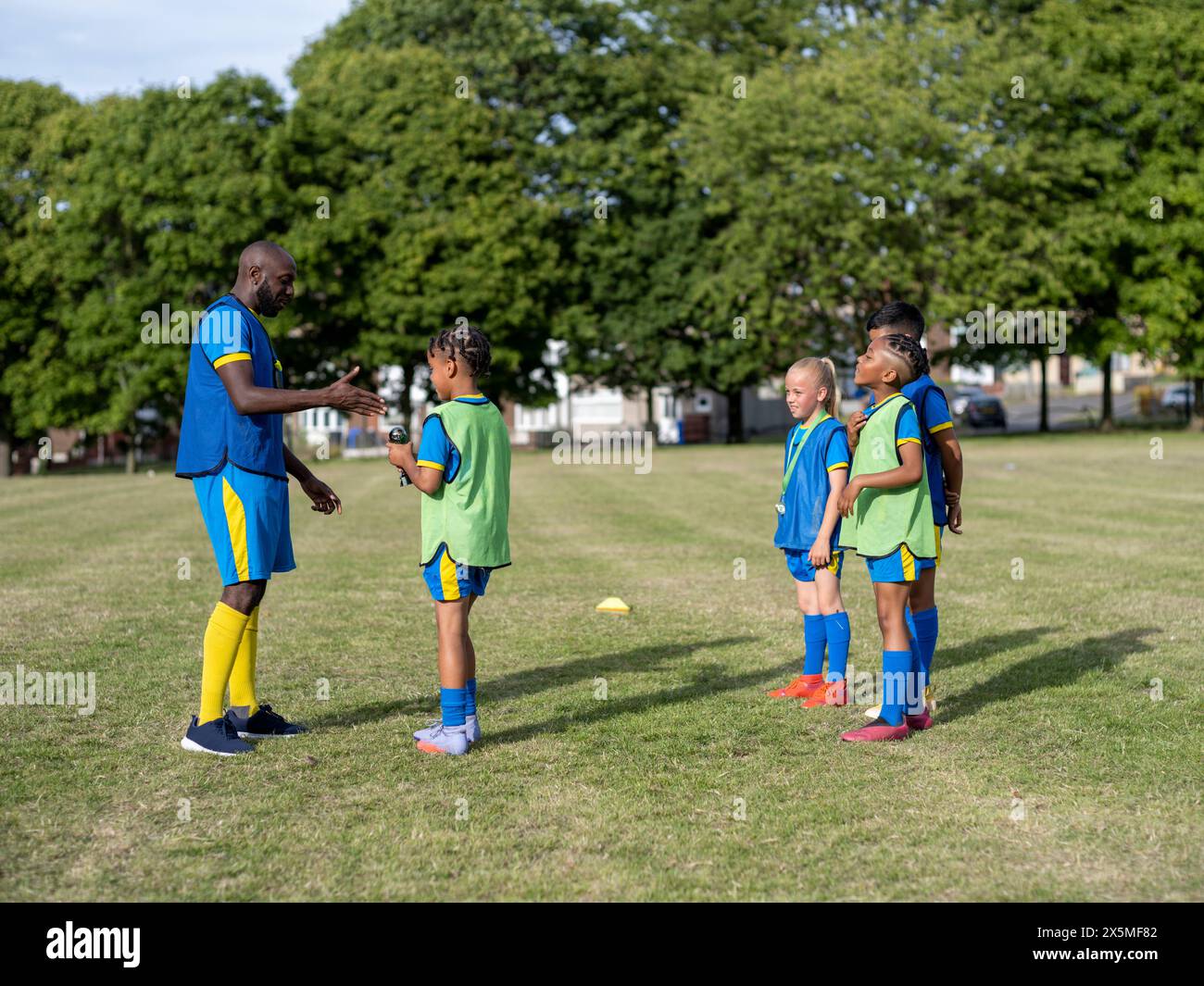 Coach giving prizes to kids (8-9) on soccer field Stock Photo - Alamy