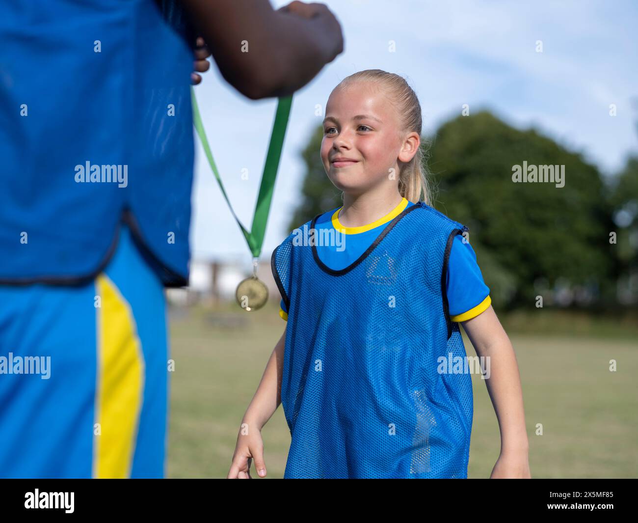 Girl (8-9) in soccer uniform receiving medal from coach Stock Photo - Alamy