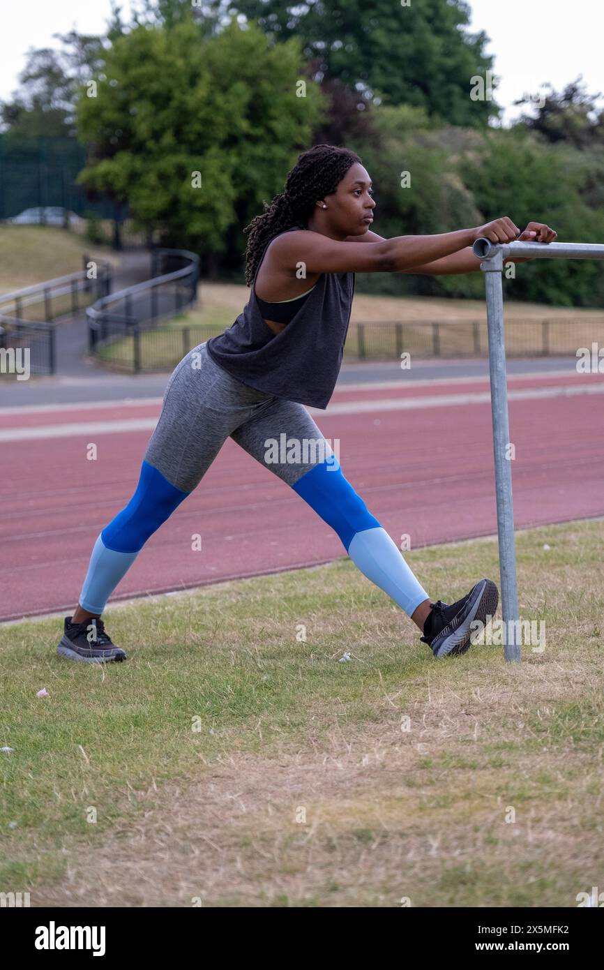Athletic woman stretching legs on running track Stock Photo - Alamy