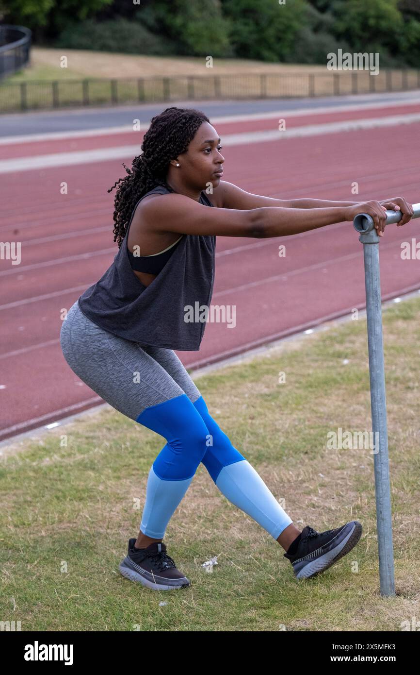 Athletic woman stretching legs on running track Stock Photo - Alamy