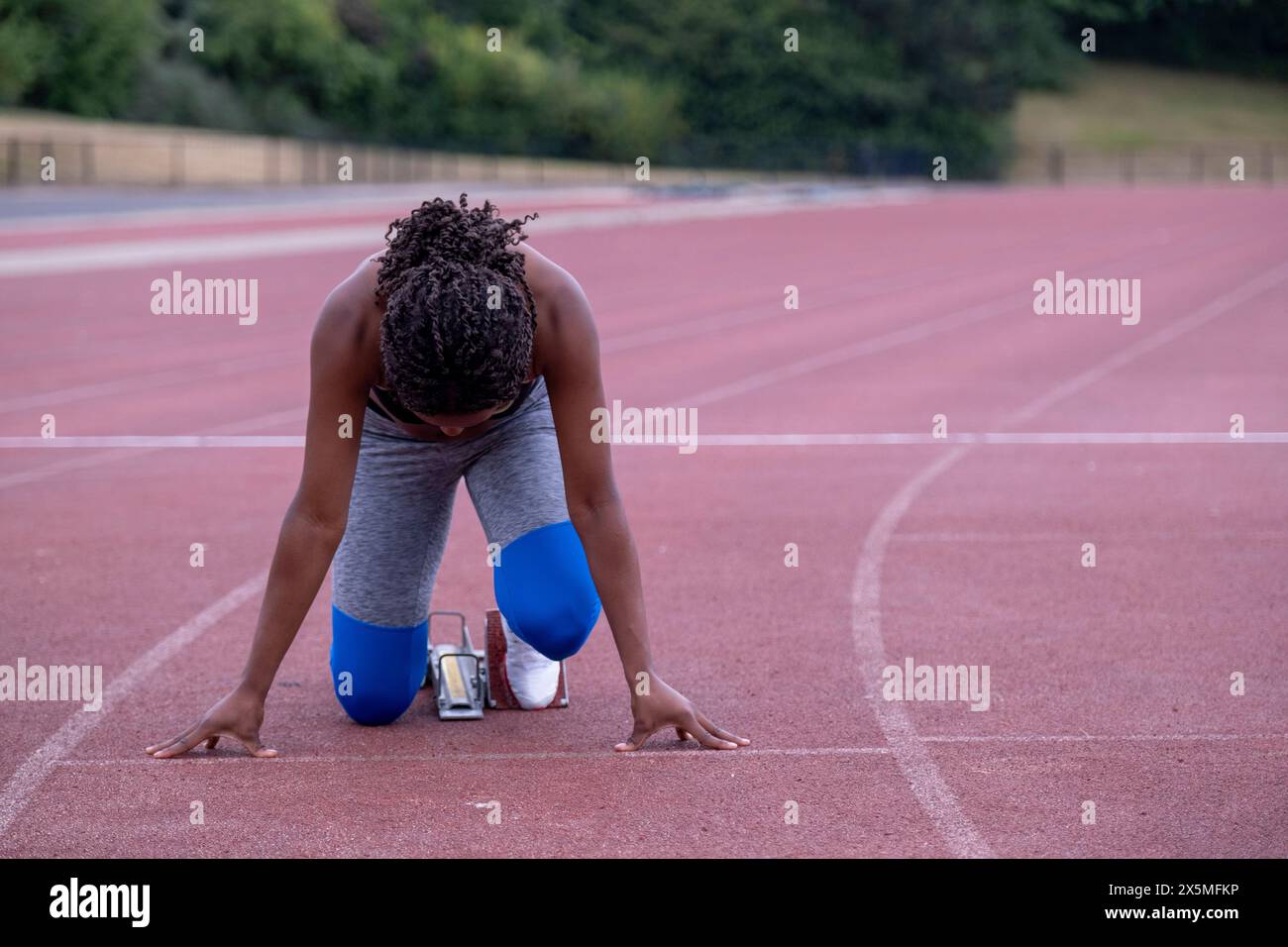 Female runner in starting position on running track Stock Photo - Alamy