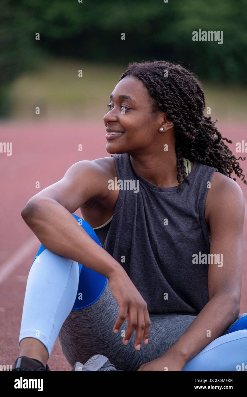Smiling athletic woman sitting on running track Stock Photo - Alamy