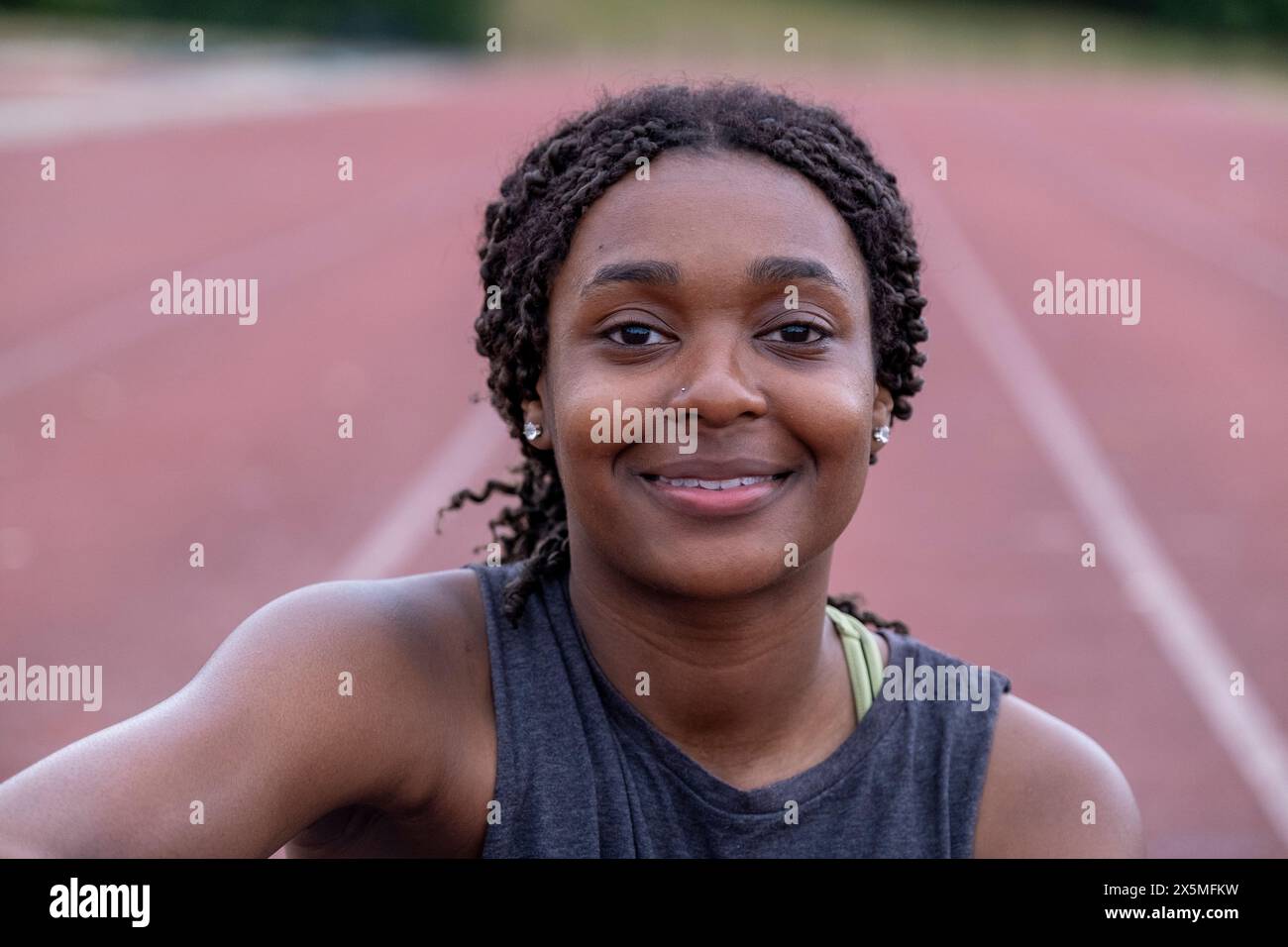 Portrait of smiling athletic woman sitting on running track Stock Photo ...