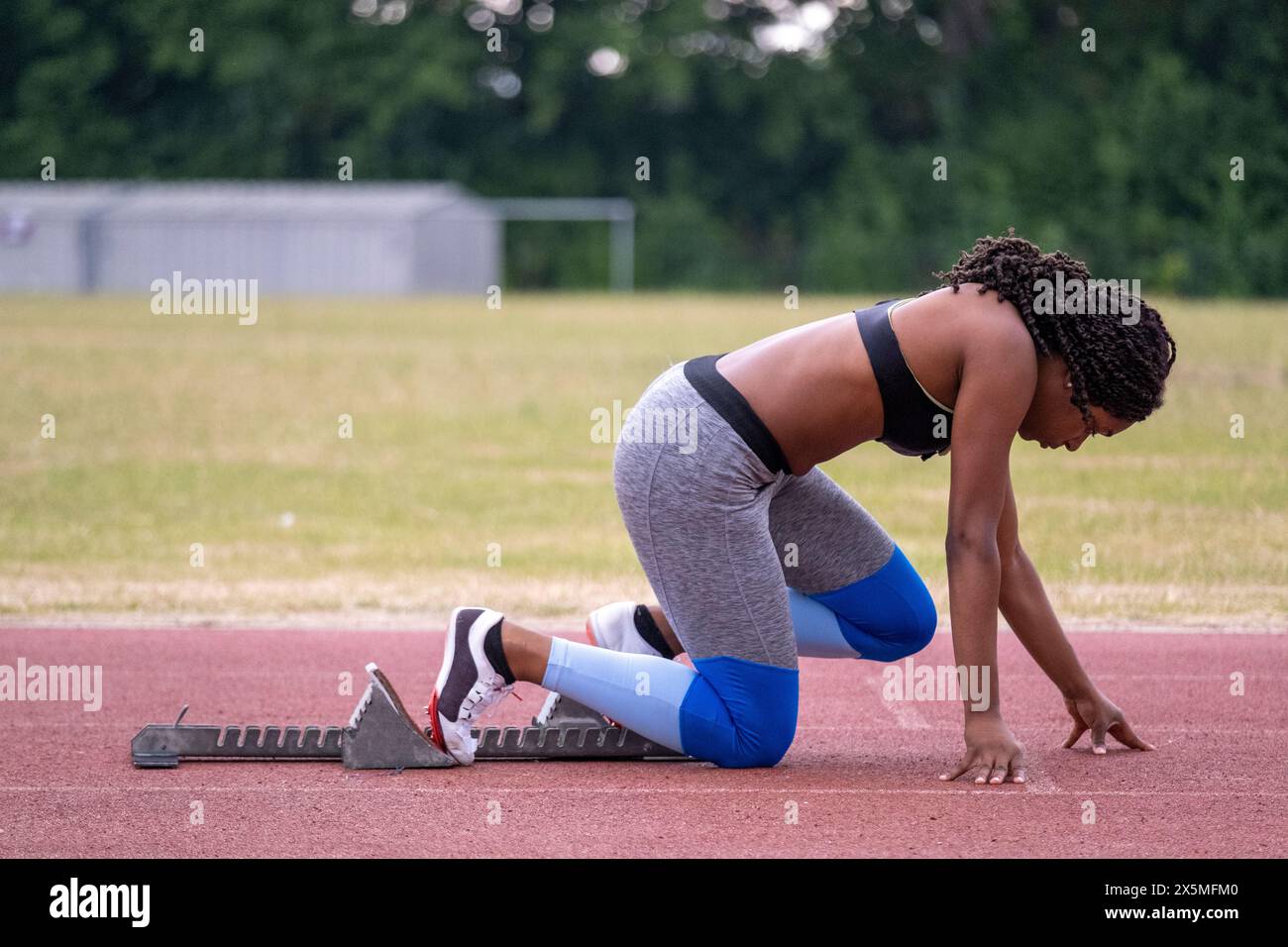 Female runner in starting position on running track Stock Photo - Alamy
