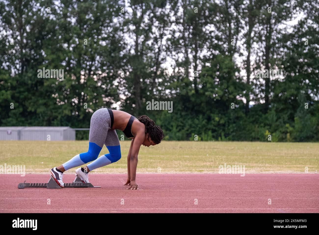 Female runner in starting position on running track Stock Photo - Alamy