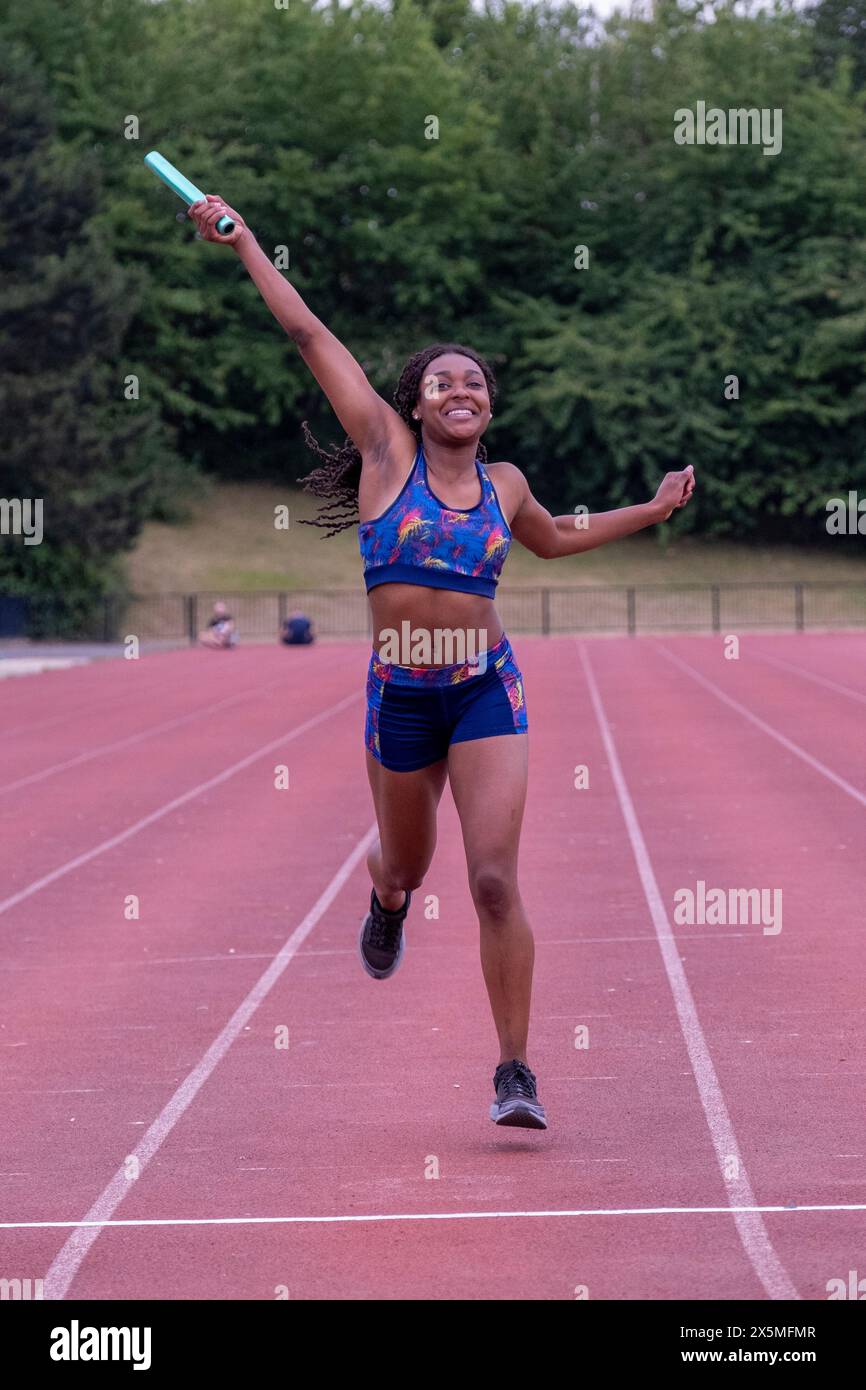 Smiling female runner with baton on running track Stock Photo - Alamy