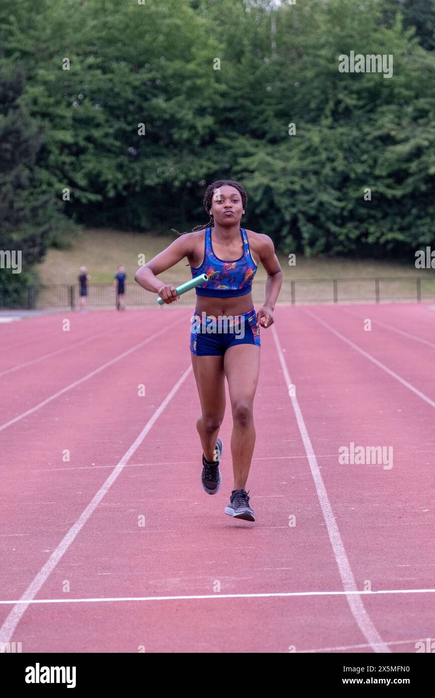 Female runner with baton on running track Stock Photo - Alamy