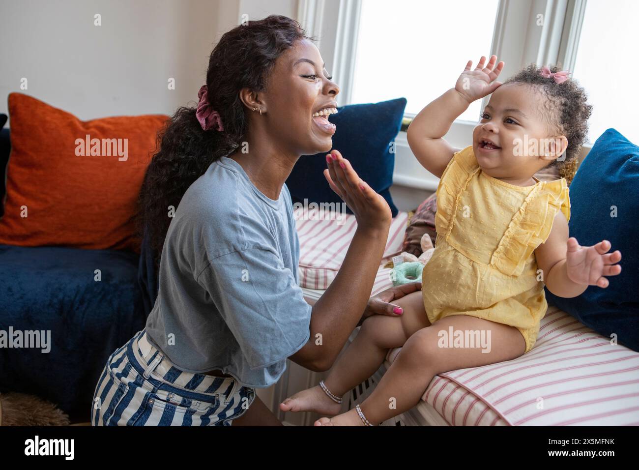 Mother giving baby daughter (12-17 months) high-five at home Stock ...