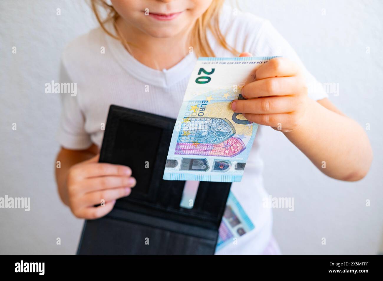 child holds black wallet in hand, kid, girl secretly takes money out of ...