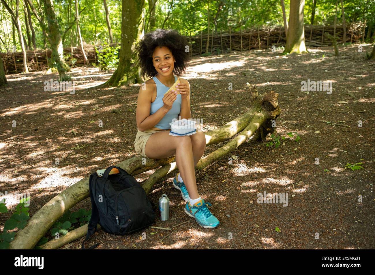 Female backpacker eating snack in forest Stock Photo - Alamy