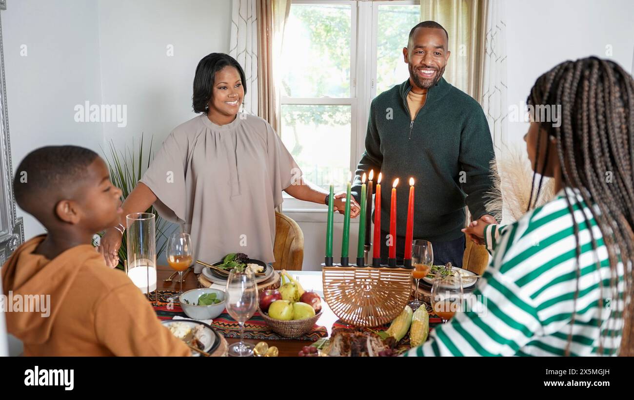 Family with children (8-9, 12-13) holding hands over Kwanzaa meal Stock ...