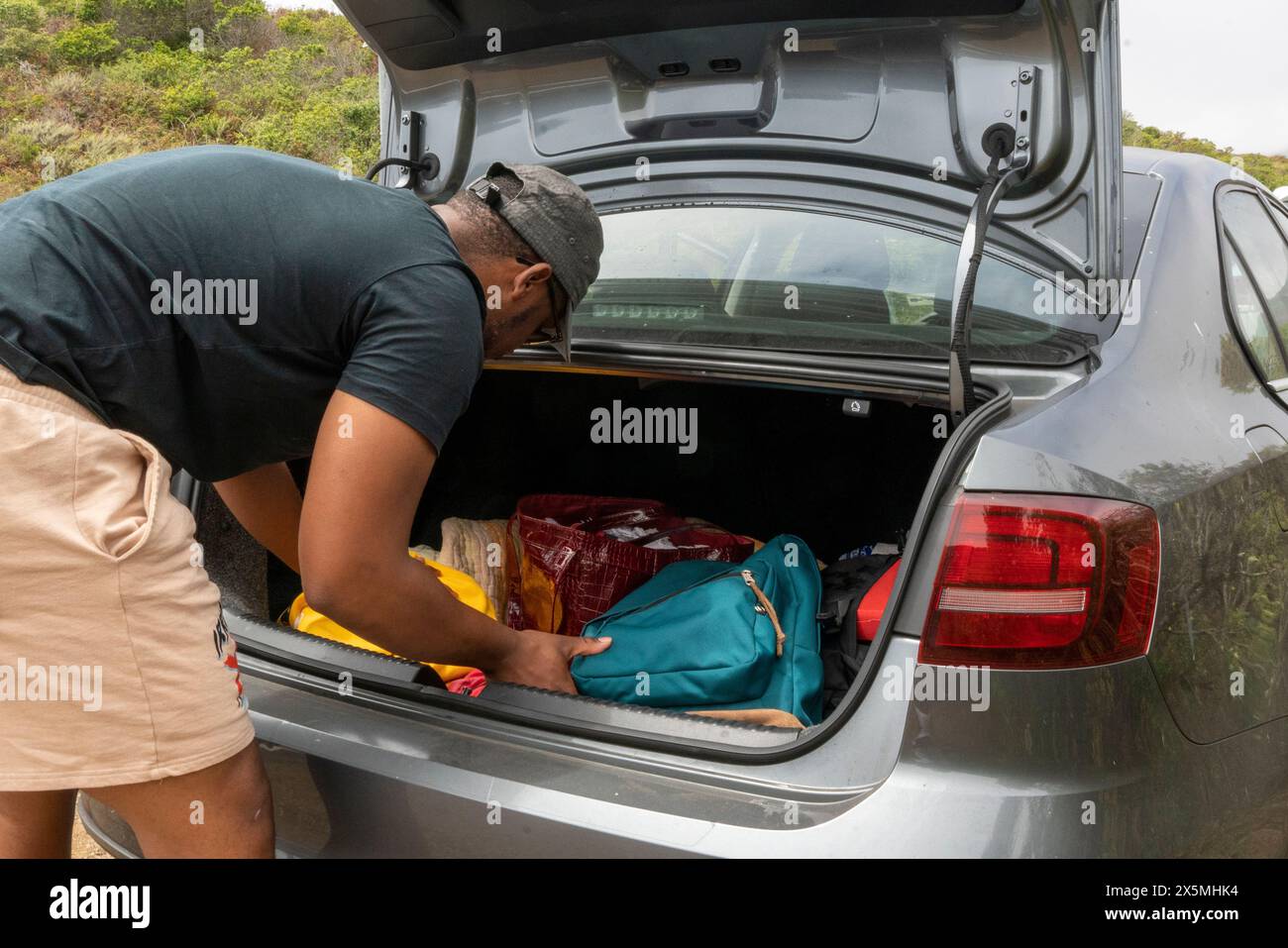 Man checking luggage in car trunk on road trip Stock Photo - Alamy