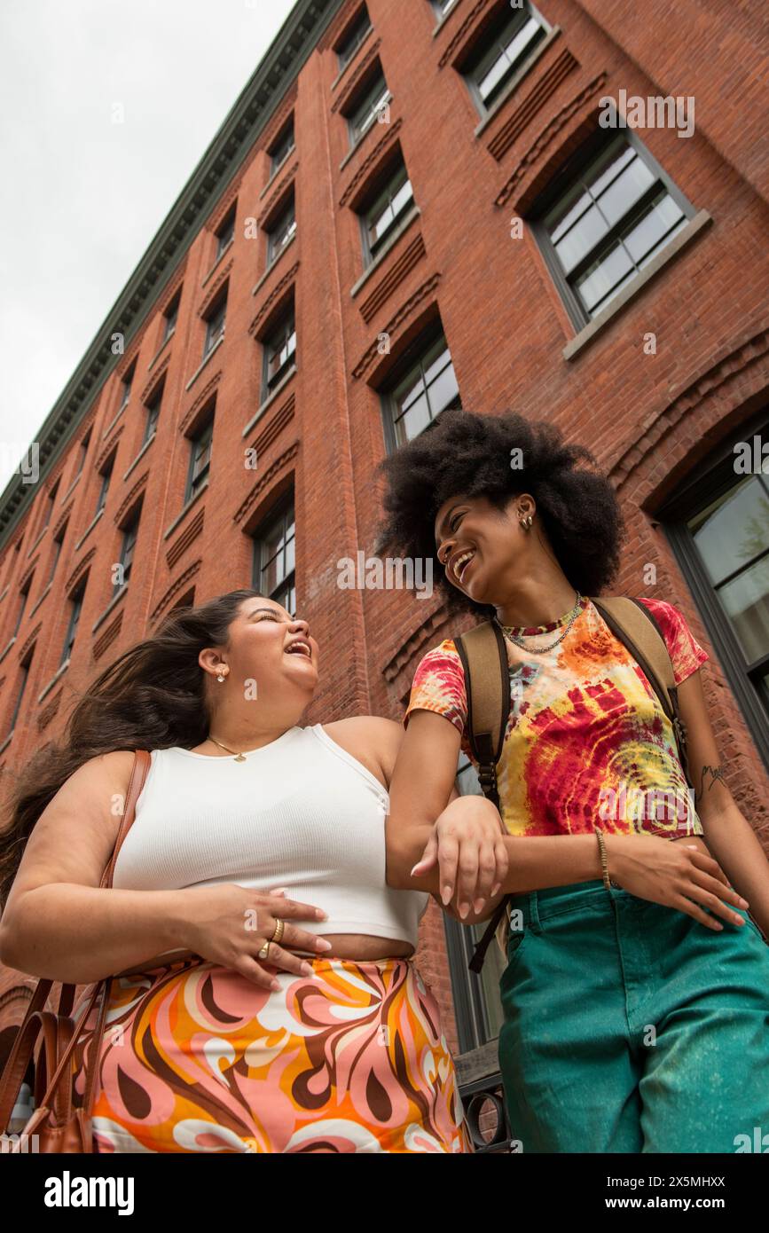 Two women in front of brick building, low angle view Stock Photo - Alamy