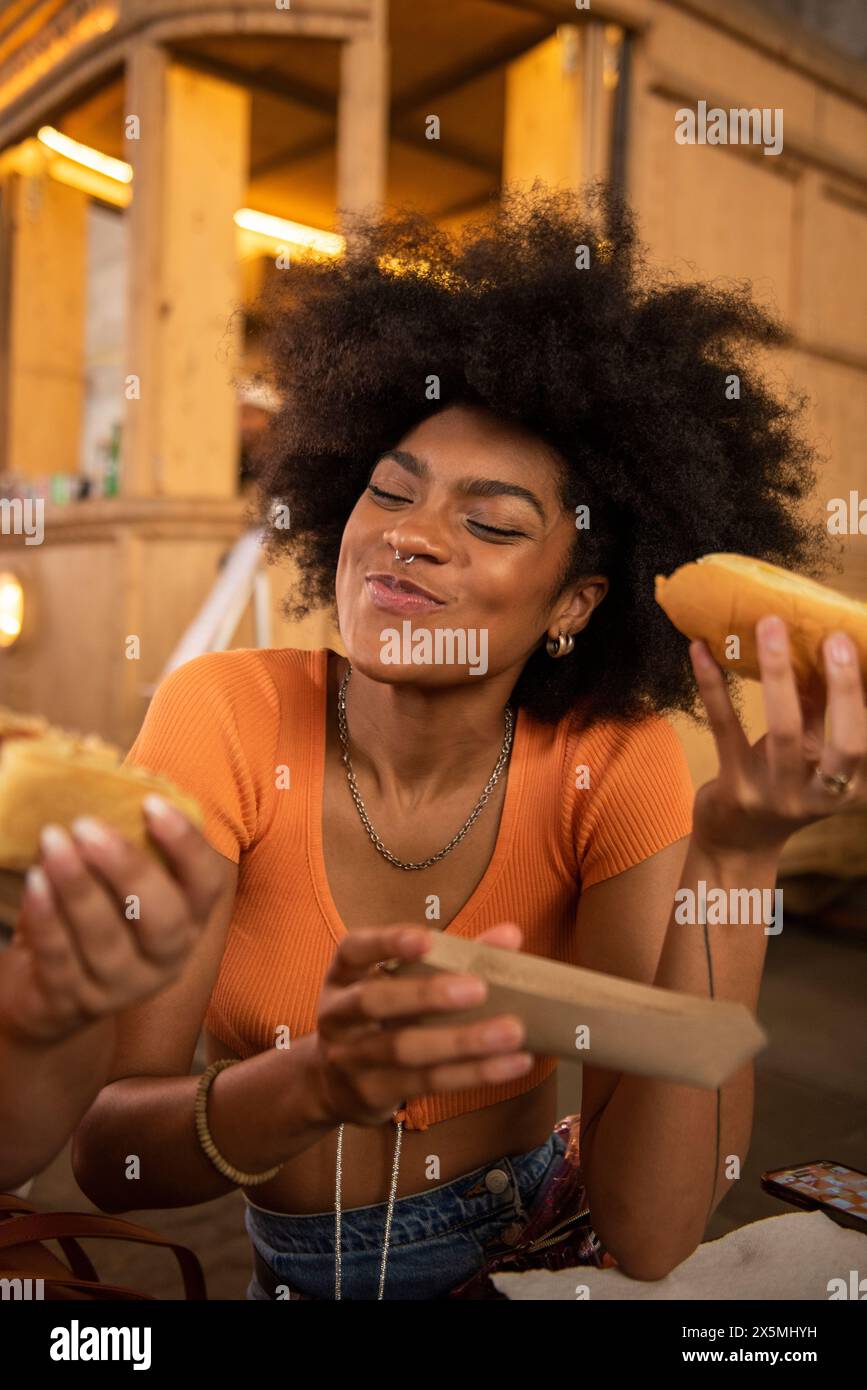 Two young women eating street food Stock Photo - Alamy