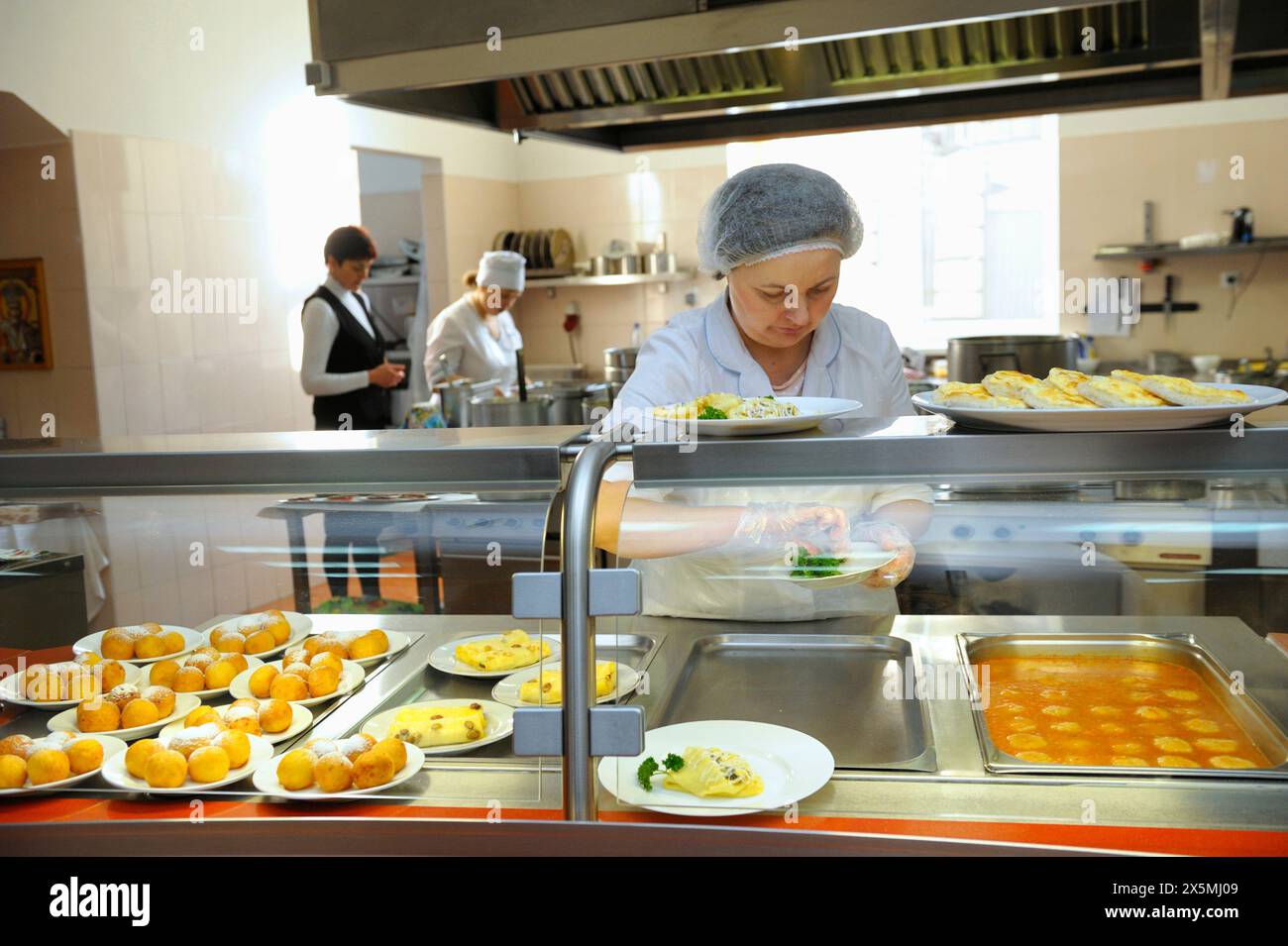 Cook sets pots and dishes on a full lunch service station of a dining ...