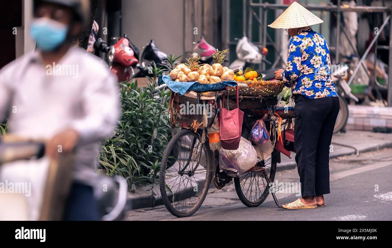 A Vietnamese street vendor woman, dressed in a traditional Asian ...
