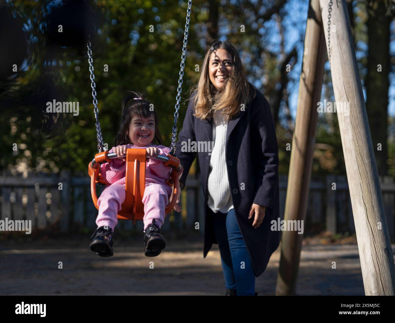 Mother swinging daughter with Down syndrome on playground swing Stock Photo - Alamy
