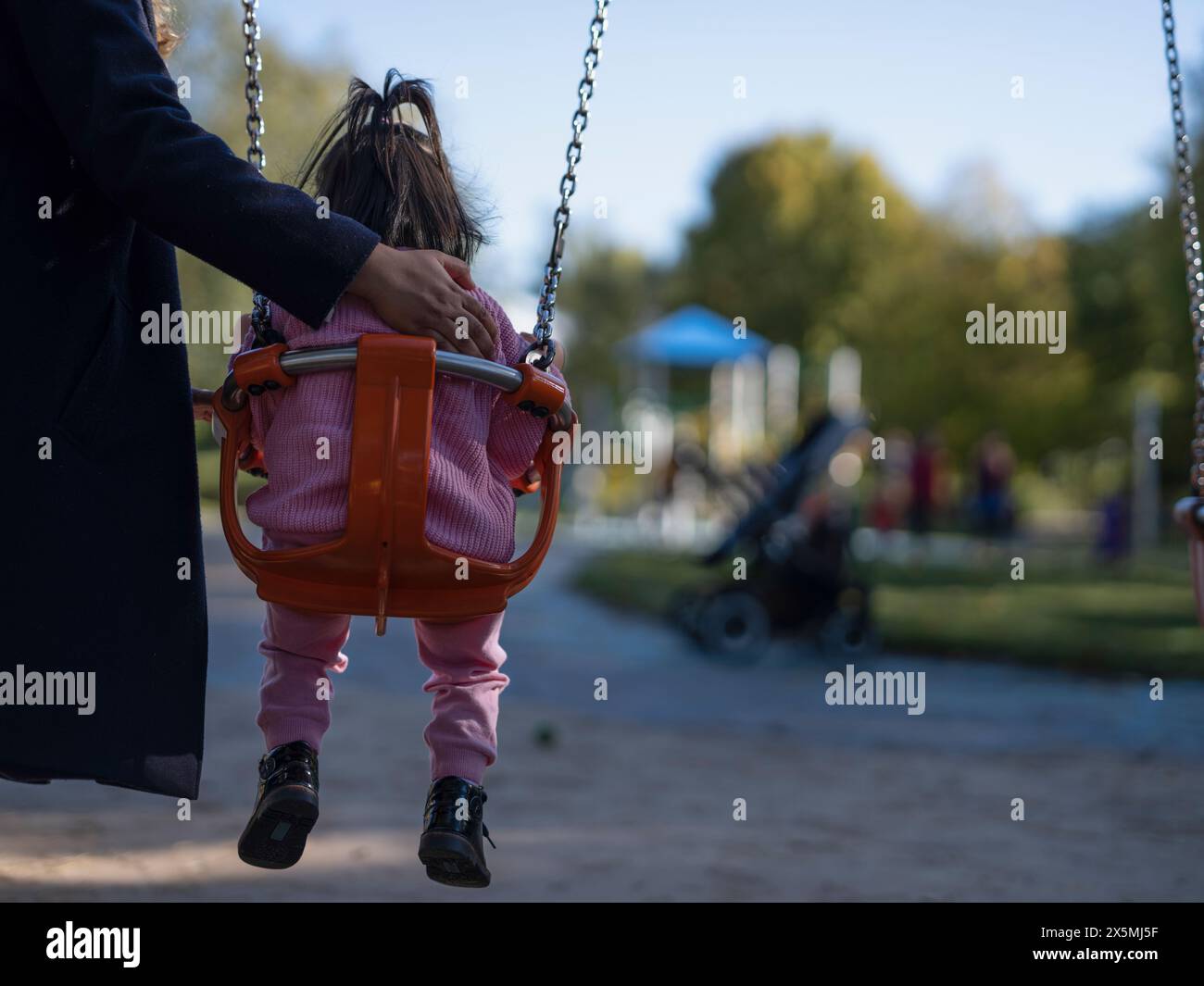 Mother swinging daughter on playground swing Stock Photo - Alamy