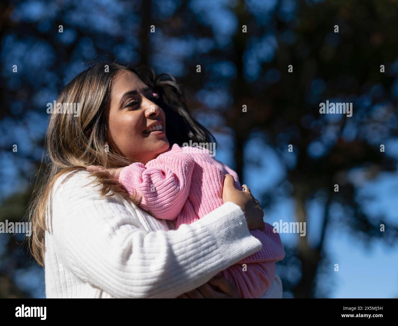 Smiling mother hugging daughter outdoors Stock Photo - Alamy