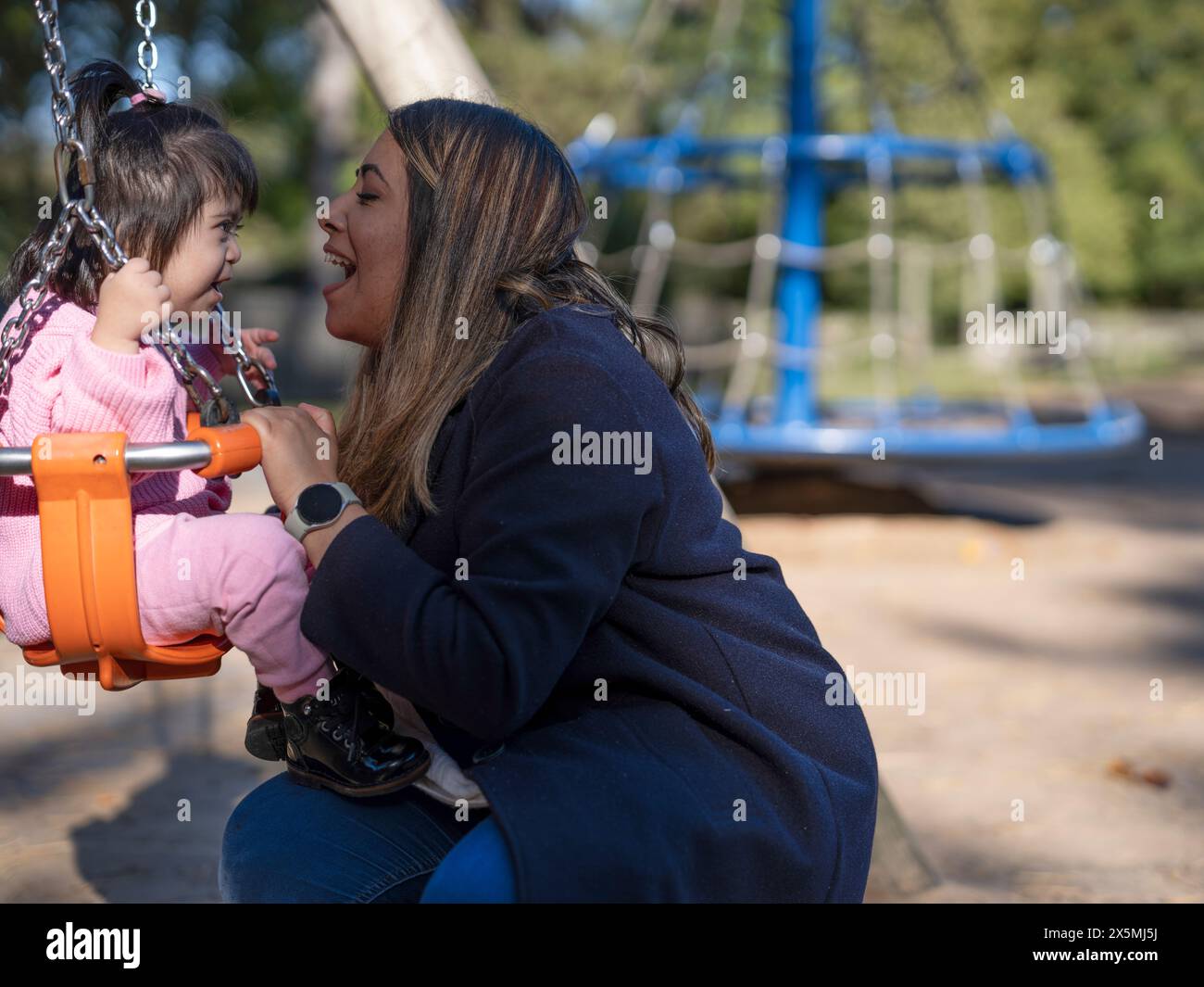 Mother swinging daughter with Down syndrome on playground swing Stock Photo - Alamy
