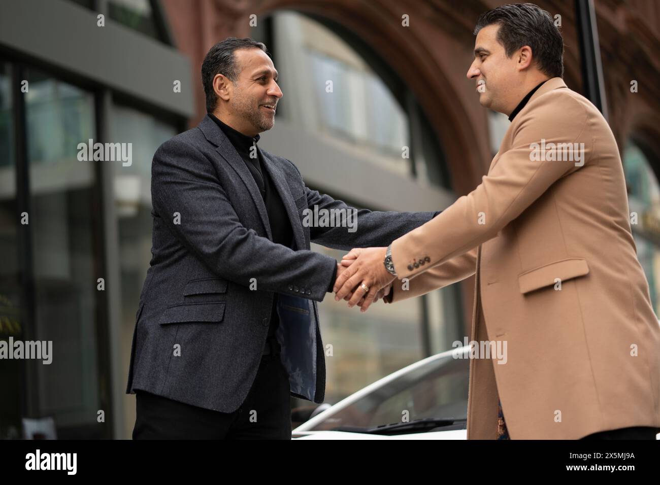 Two businessmen shaking hands in street Stock Photo - Alamy