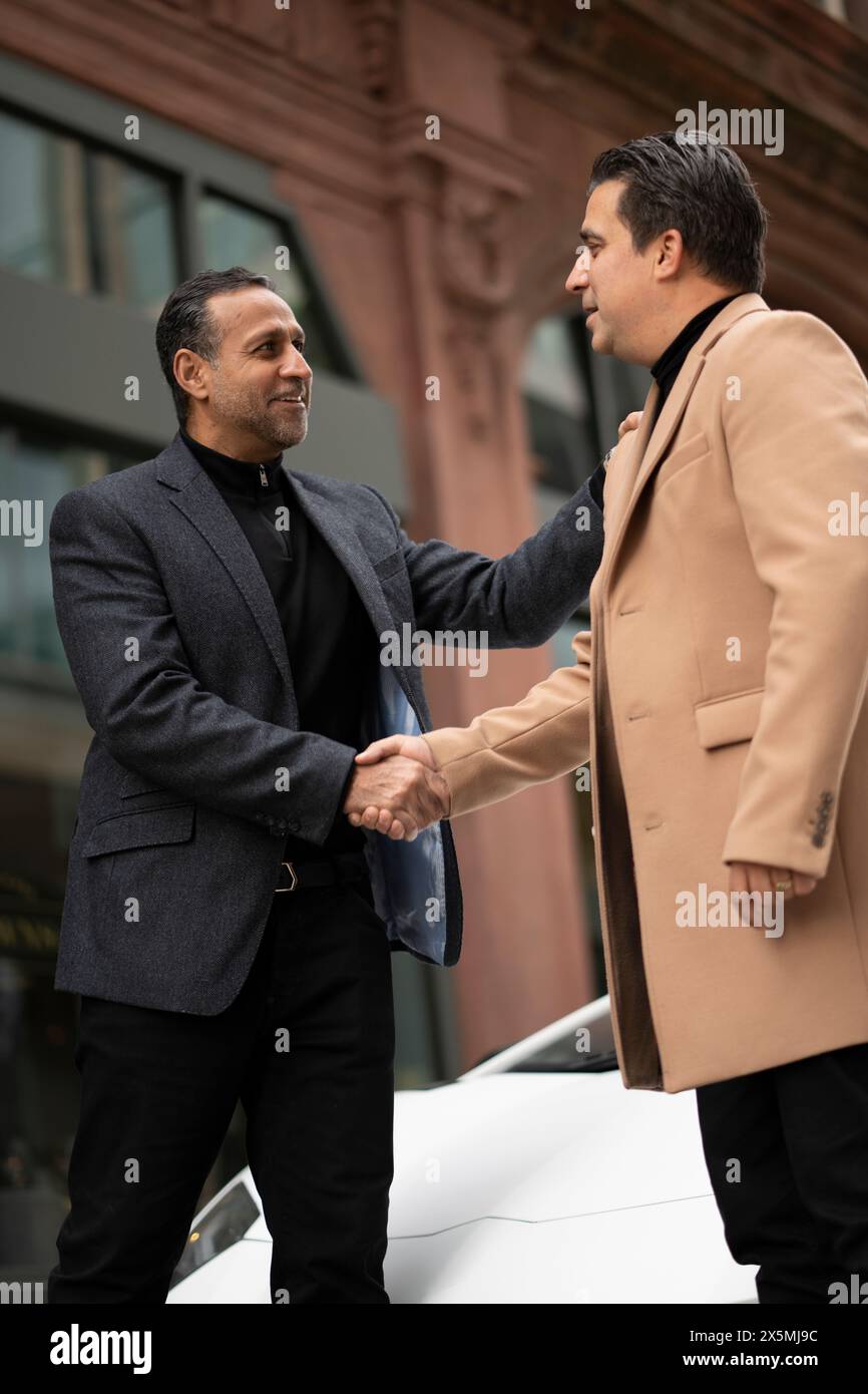 Two businessmen shaking hands in street Stock Photo - Alamy