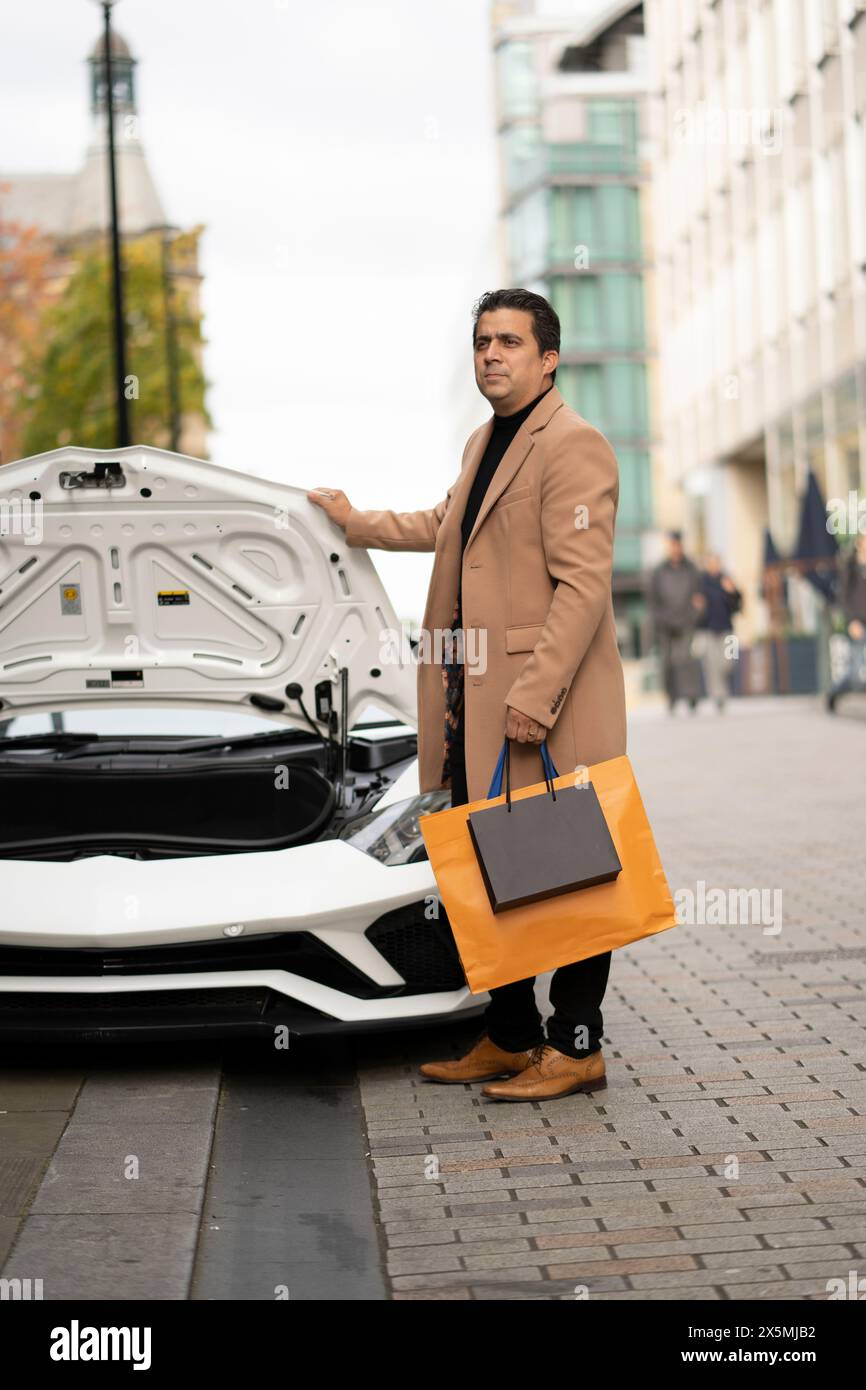 Man with shopping bags standing by luxury car Stock Photo - Alamy