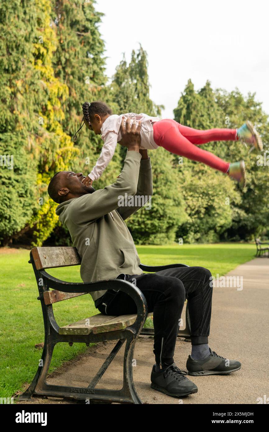 Smiling man playing with daughter on bench in park Stock Photo - Alamy