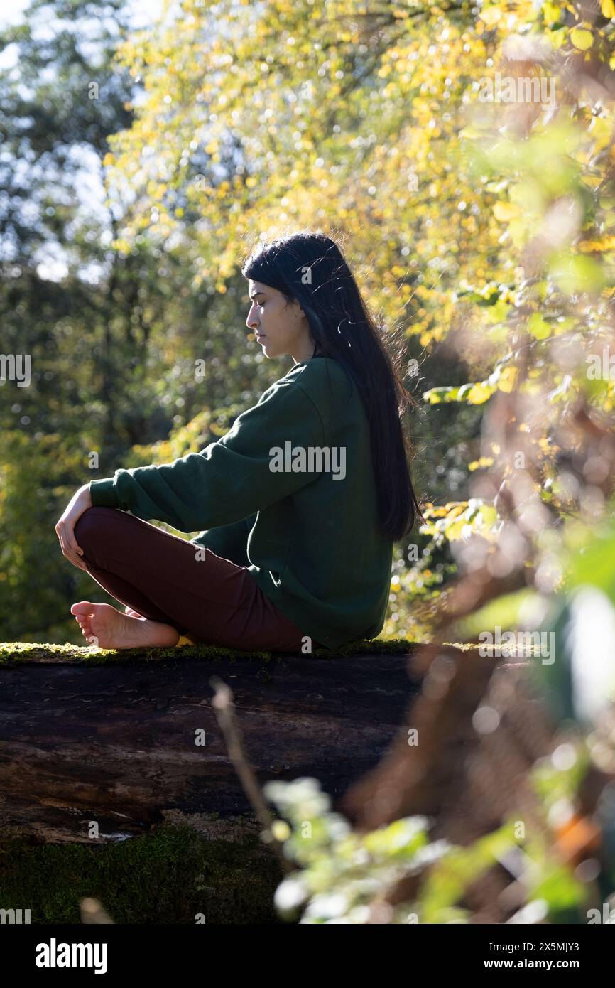 Young woman sitting on log hi-res stock photography and images - Alamy