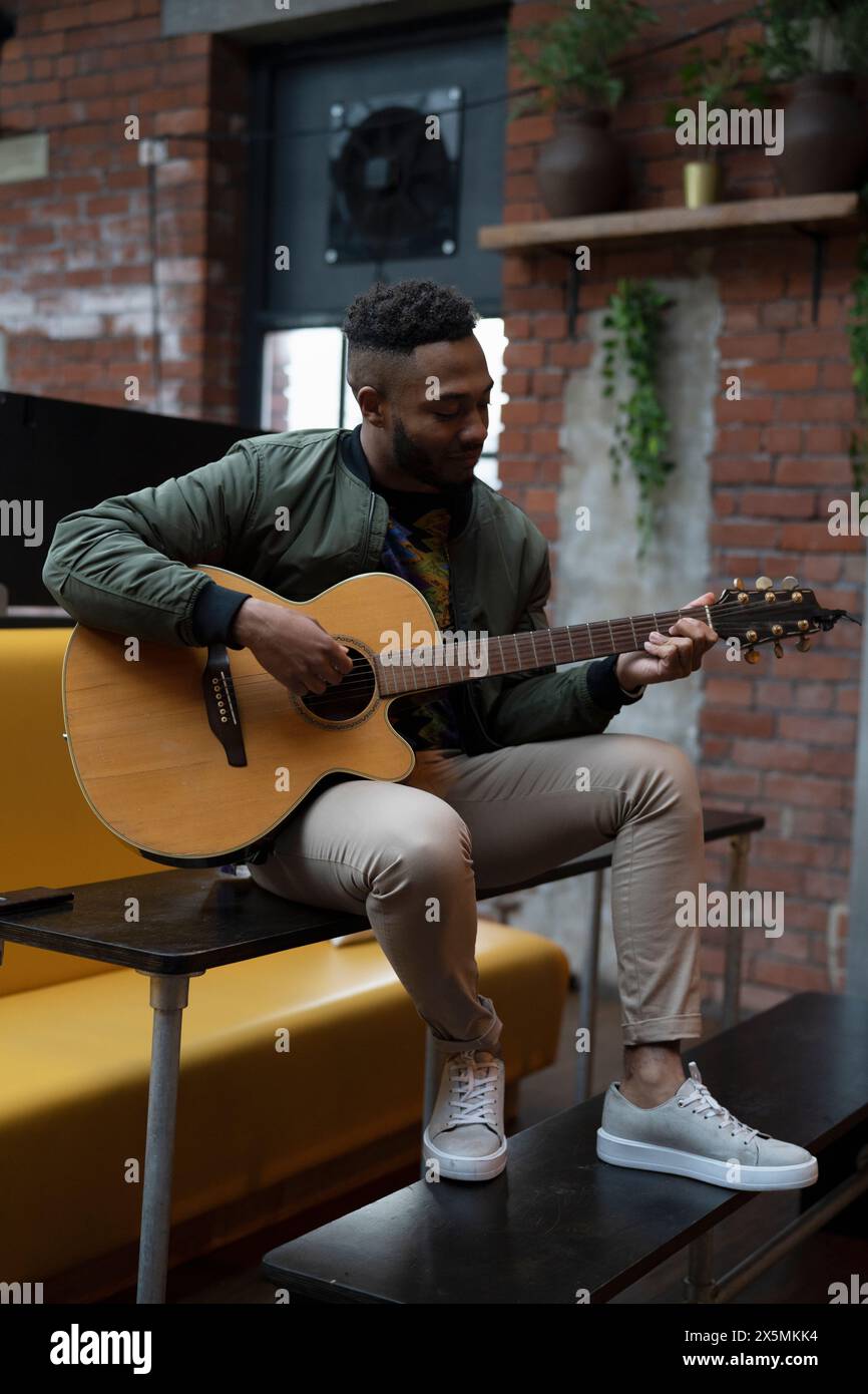 Young man playing acoustic guitar in office lounge Stock Photo - Alamy