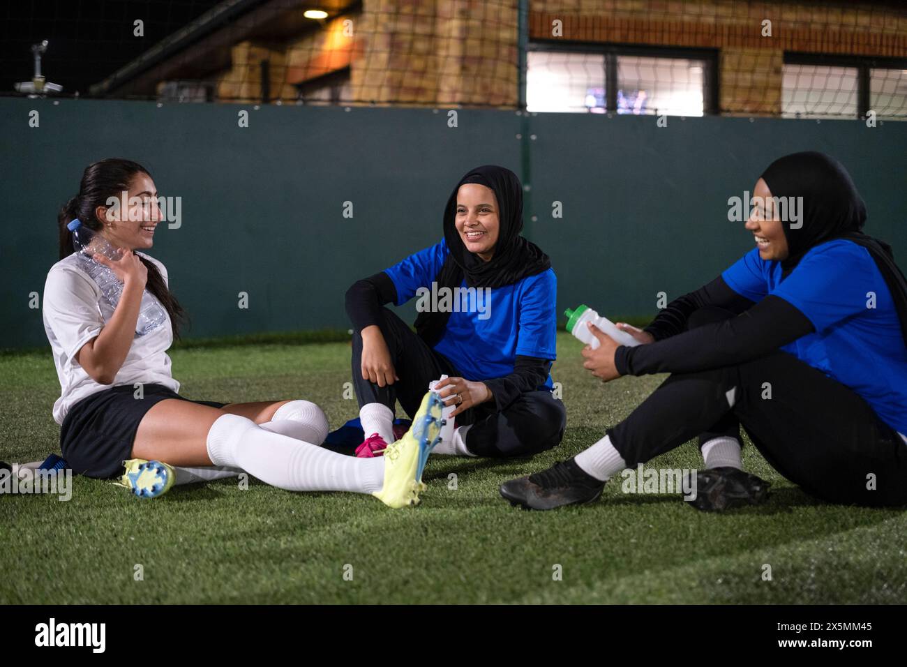 Female soccer players sitting and laughing Stock Photo - Alamy