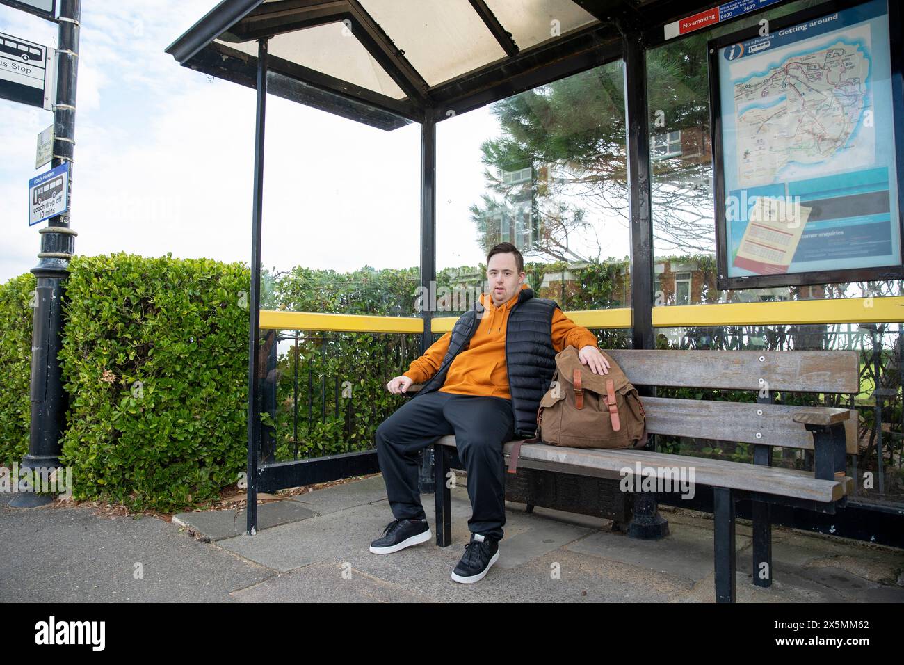 Man sitting on bench at bus stop Stock Photo - Alamy