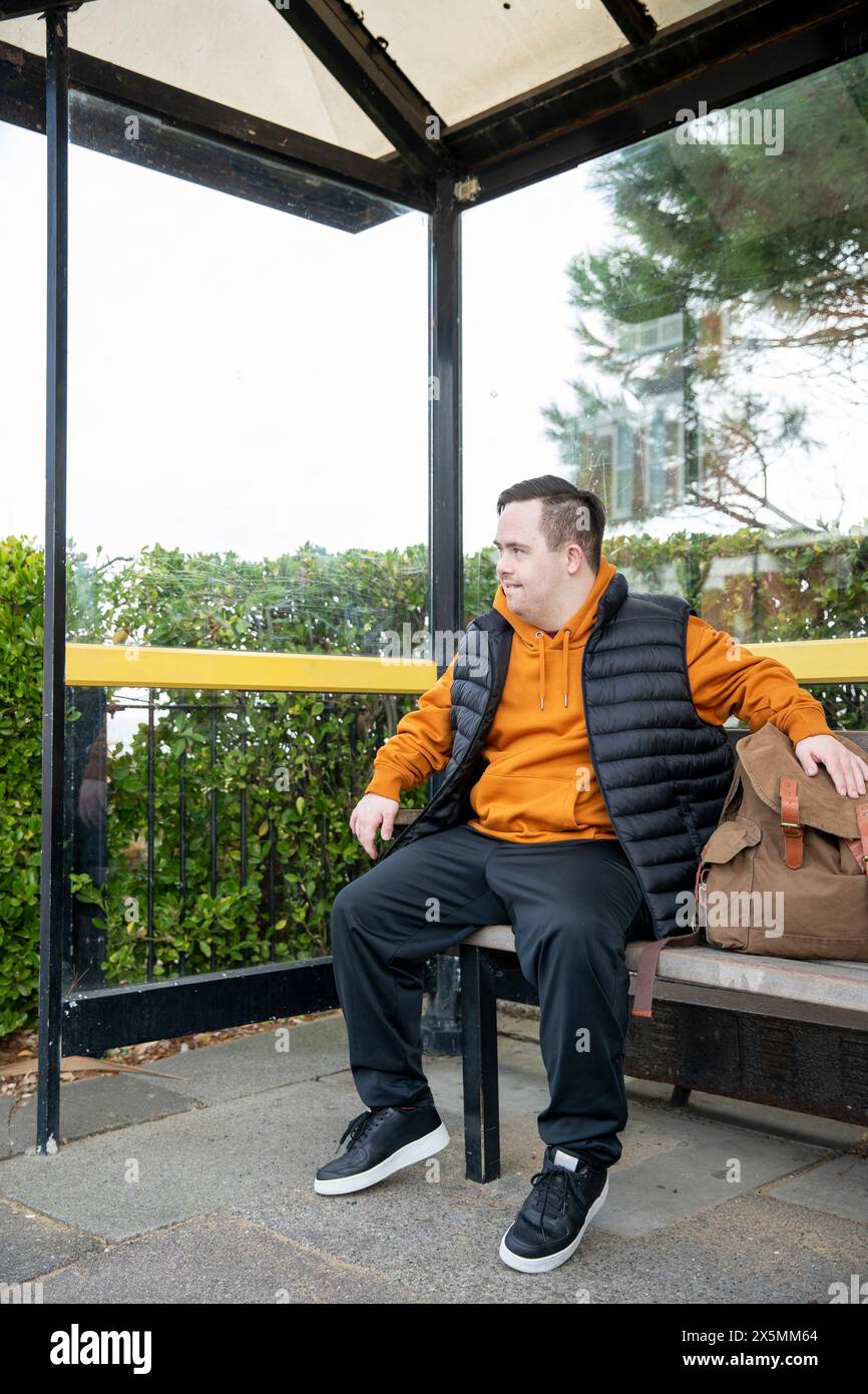 Man sitting on bench at bus stop Stock Photo - Alamy
