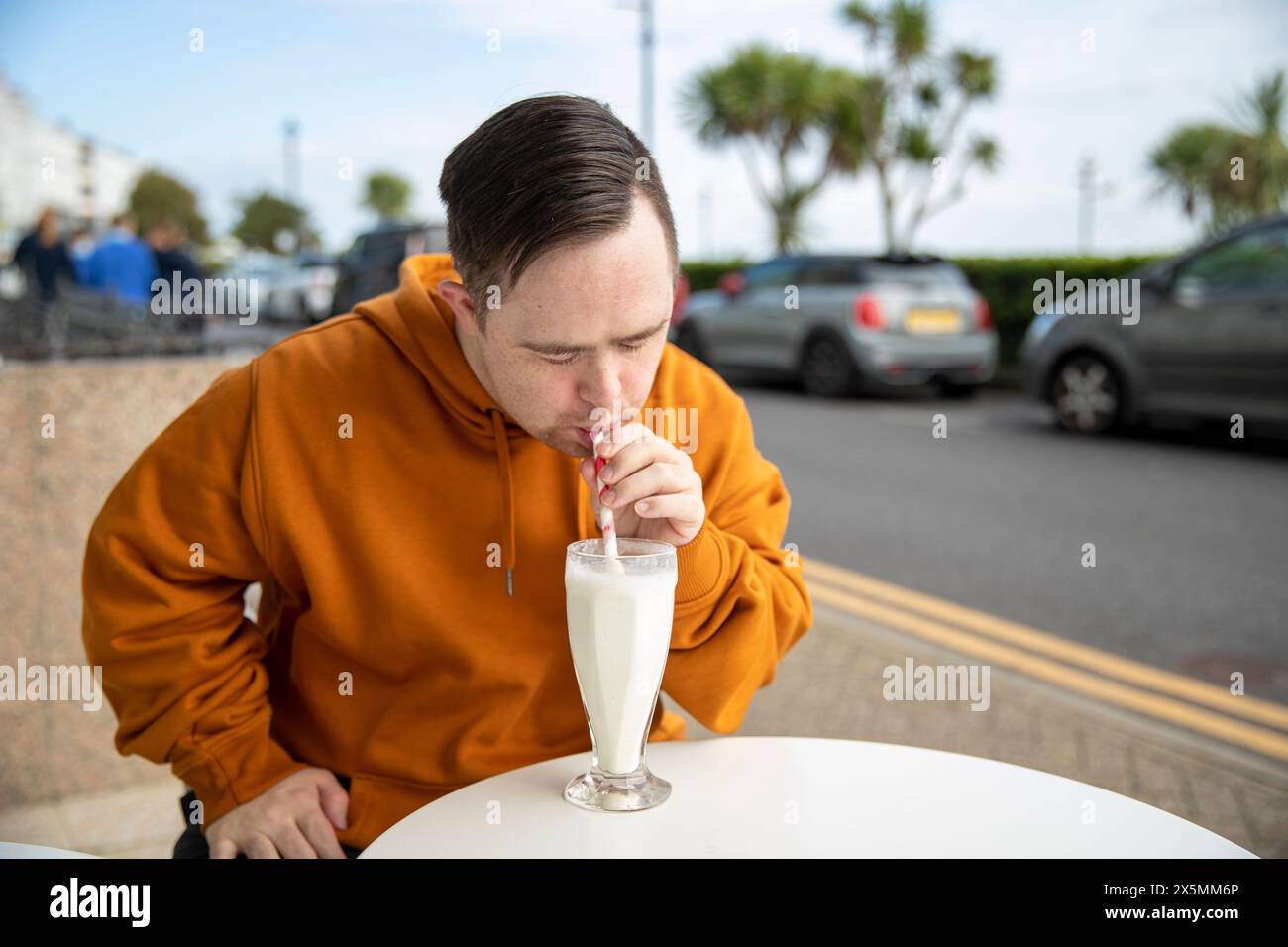 Man drinking milkshake in sidewalk cafe Stock Photo - Alamy