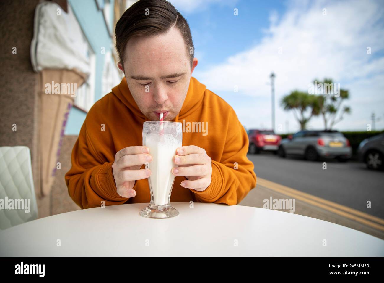 Man drinking milkshake in sidewalk cafe Stock Photo - Alamy