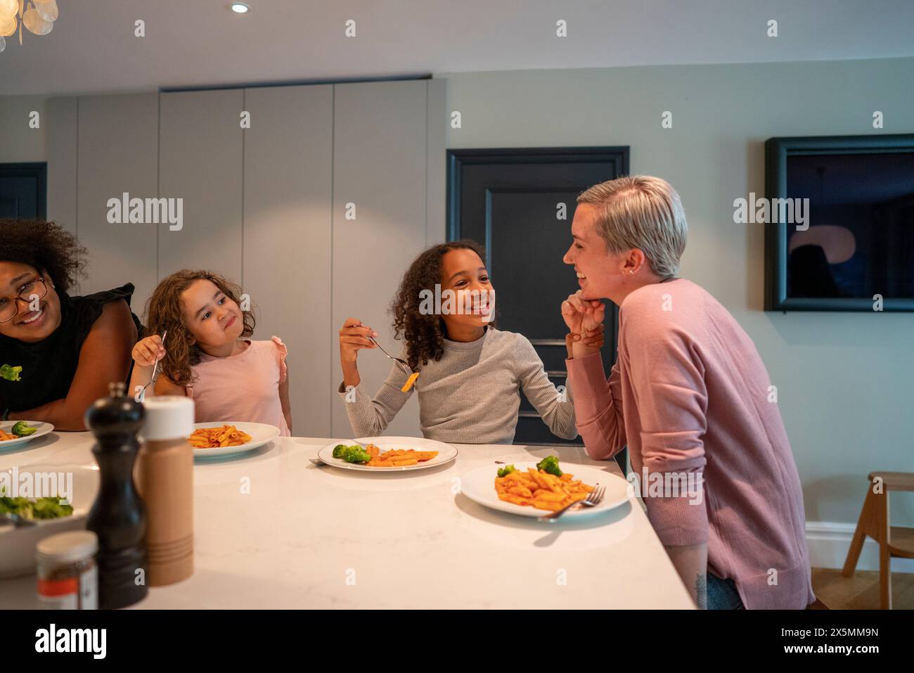 Mother with three daughters enjoying dinner in kitchen Stock Photo - Alamy