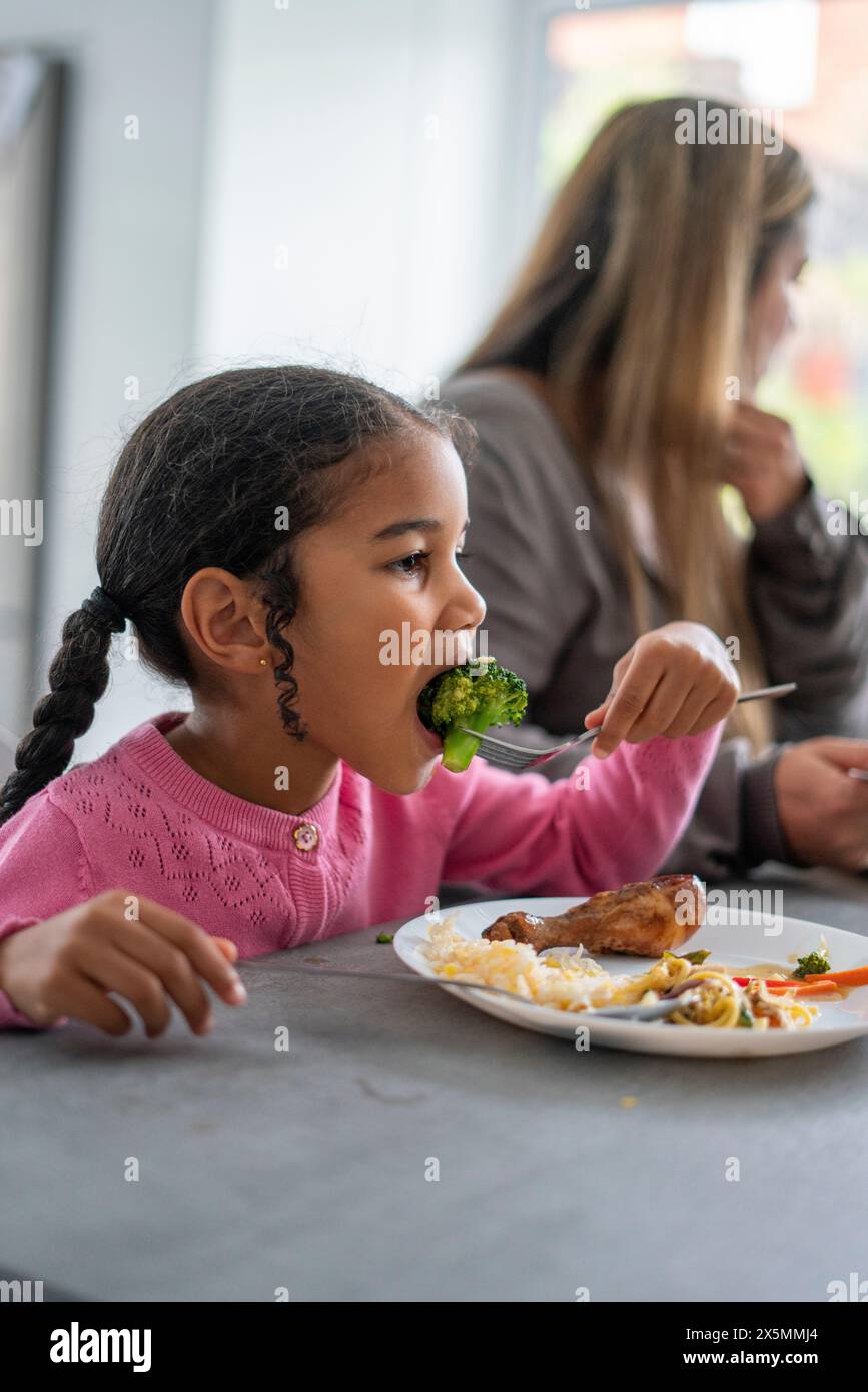 Girl eating dinner with family Stock Photo - Alamy