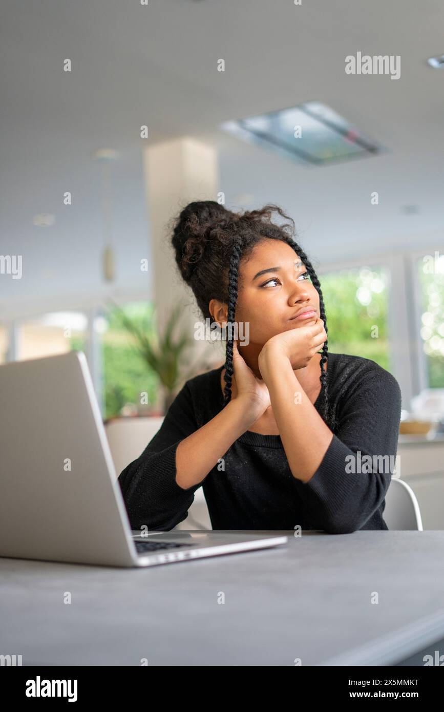 Teenage girl using laptop and thinking Stock Photo - Alamy
