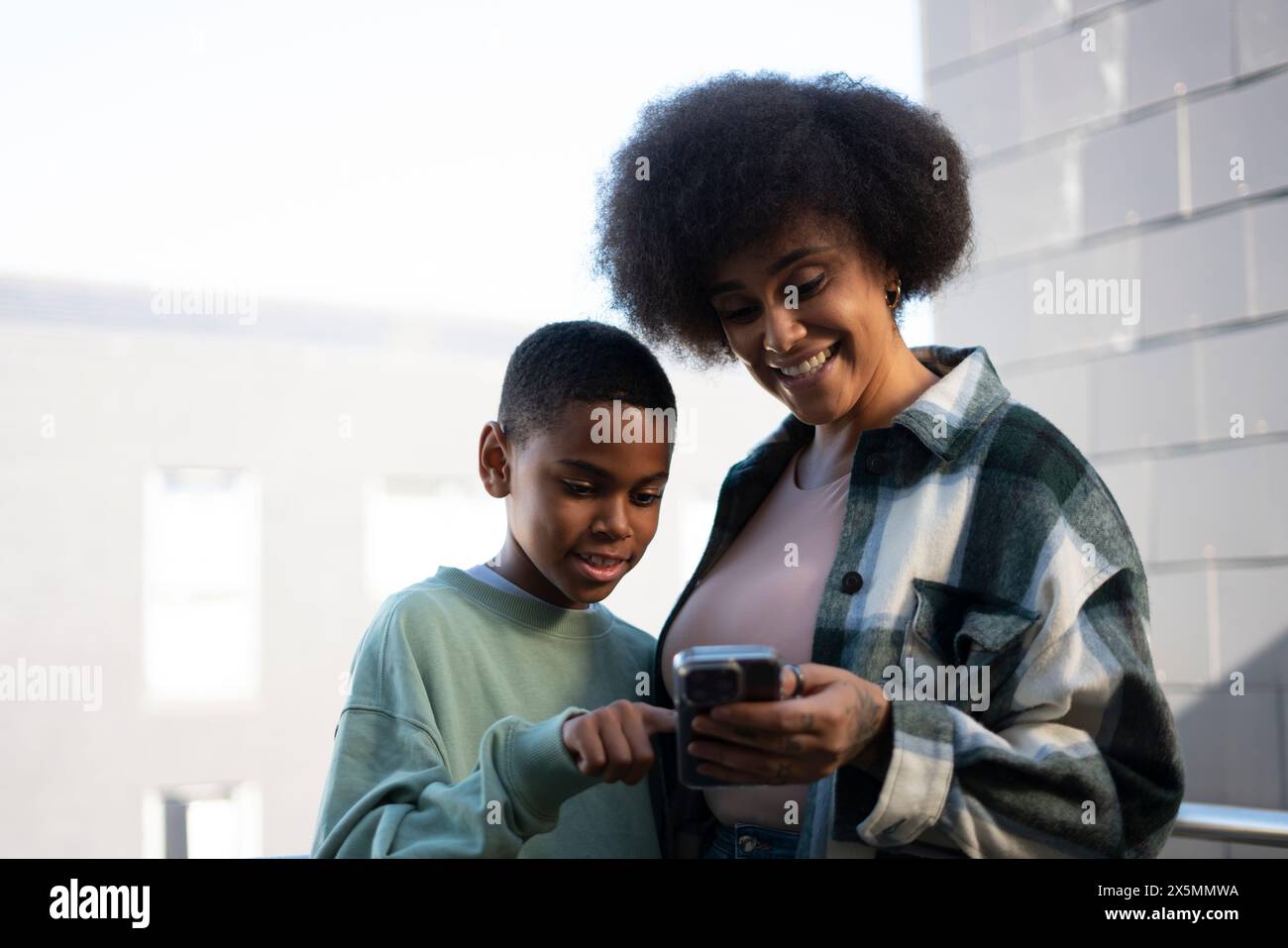 Smiling mother and son using smart phone Stock Photo - Alamy