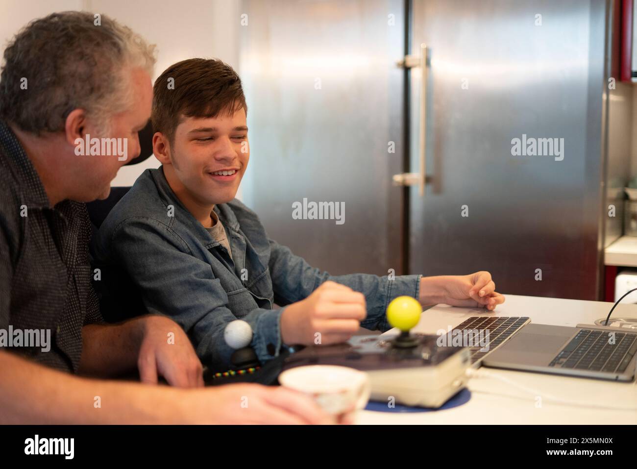 Disabled son using laptop with father Stock Photo - Alamy