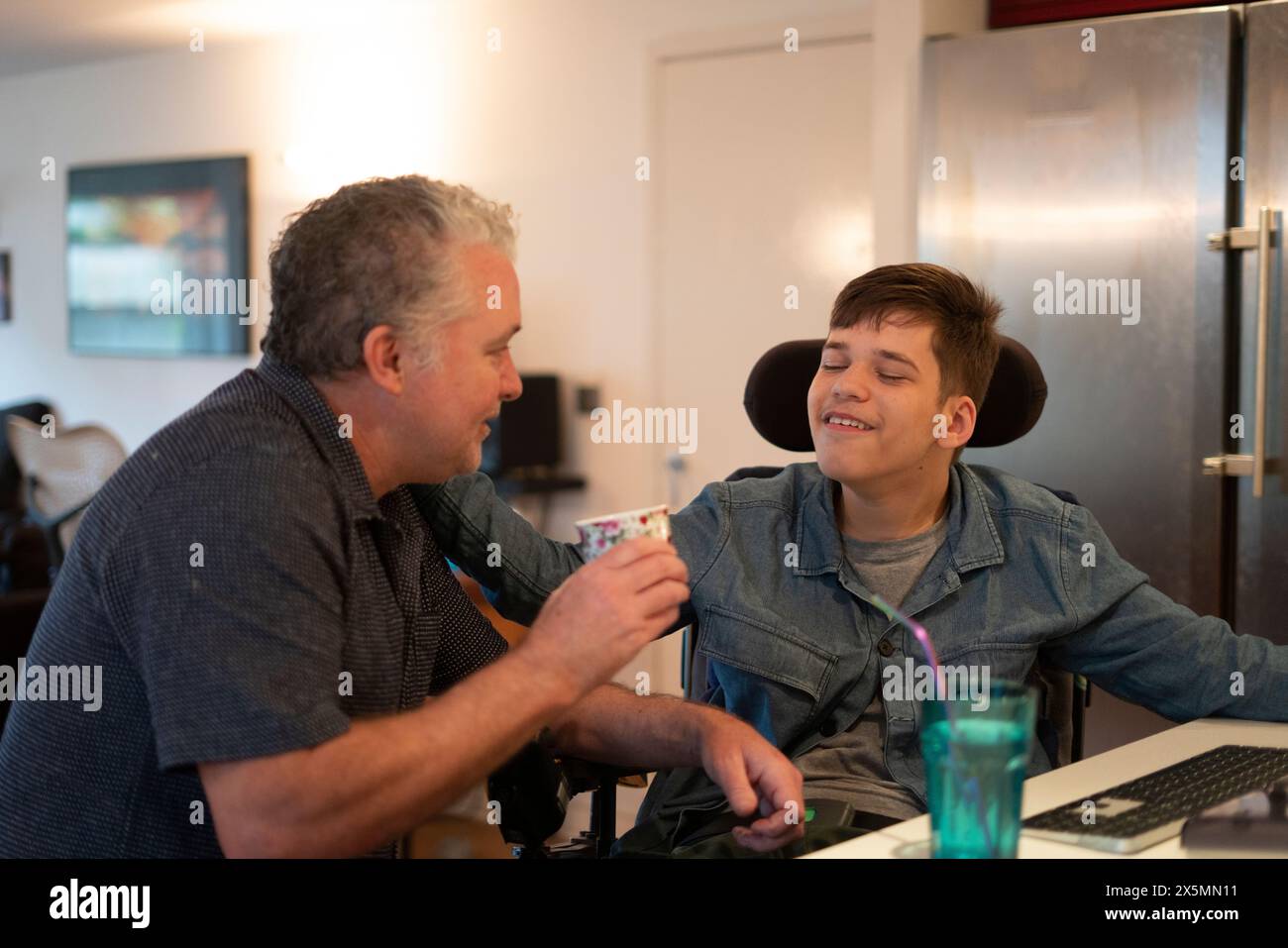 Father talking with disabled son at home Stock Photo - Alamy