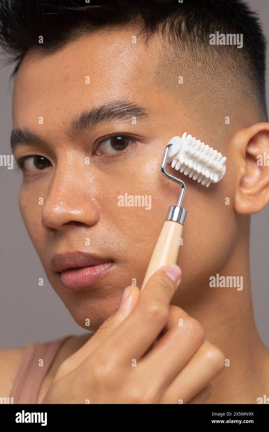 Studio portrait of person using face roller Stock Photo - Alamy