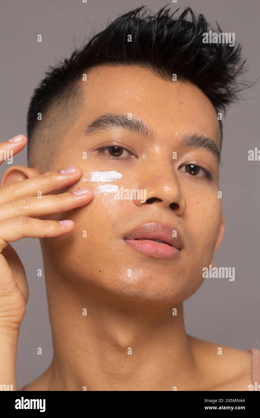 Studio portrait of person applying?moisturizer?on face Stock Photo - Alamy