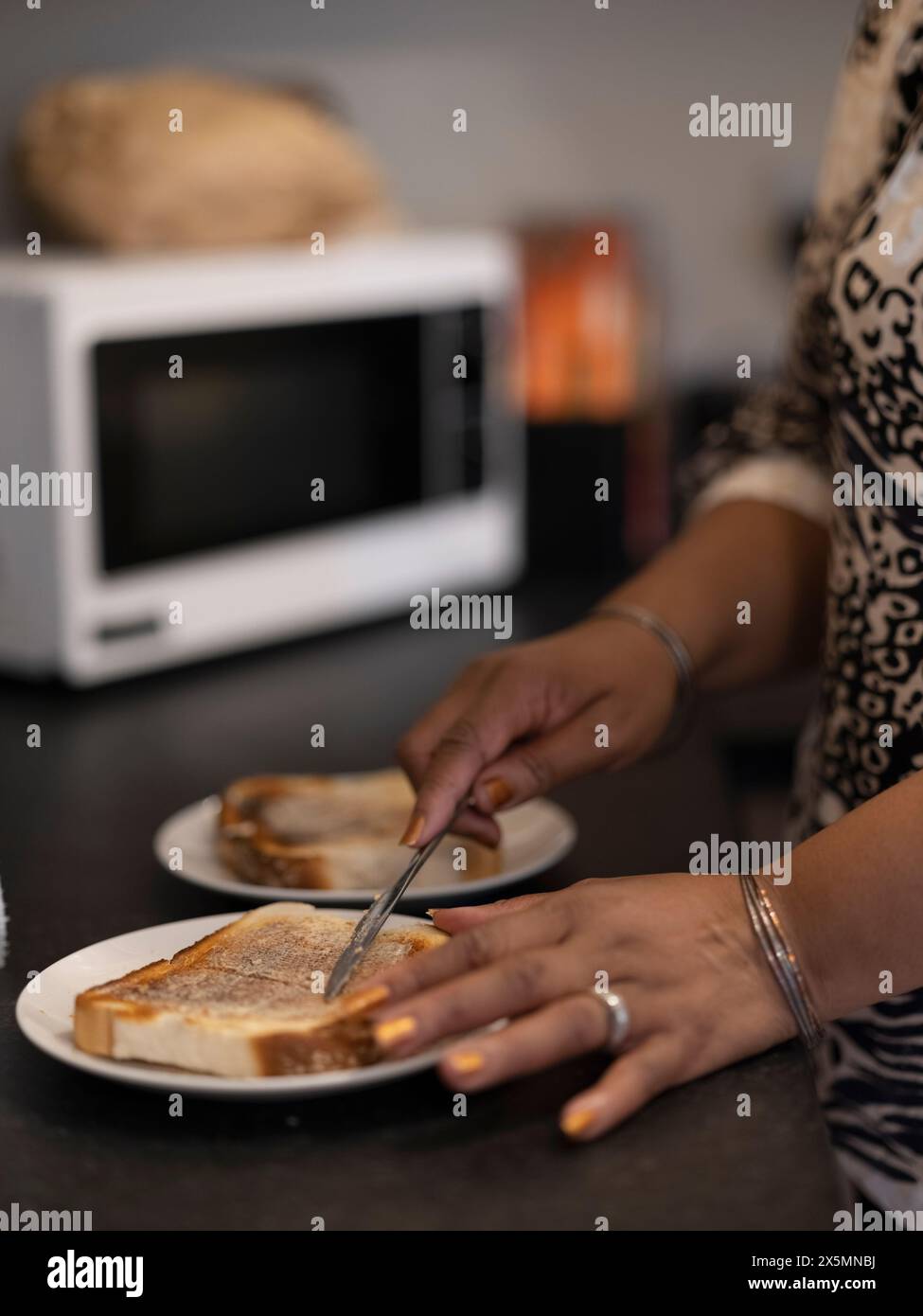 Woman buttering toast in kitchen Stock Photo - Alamy