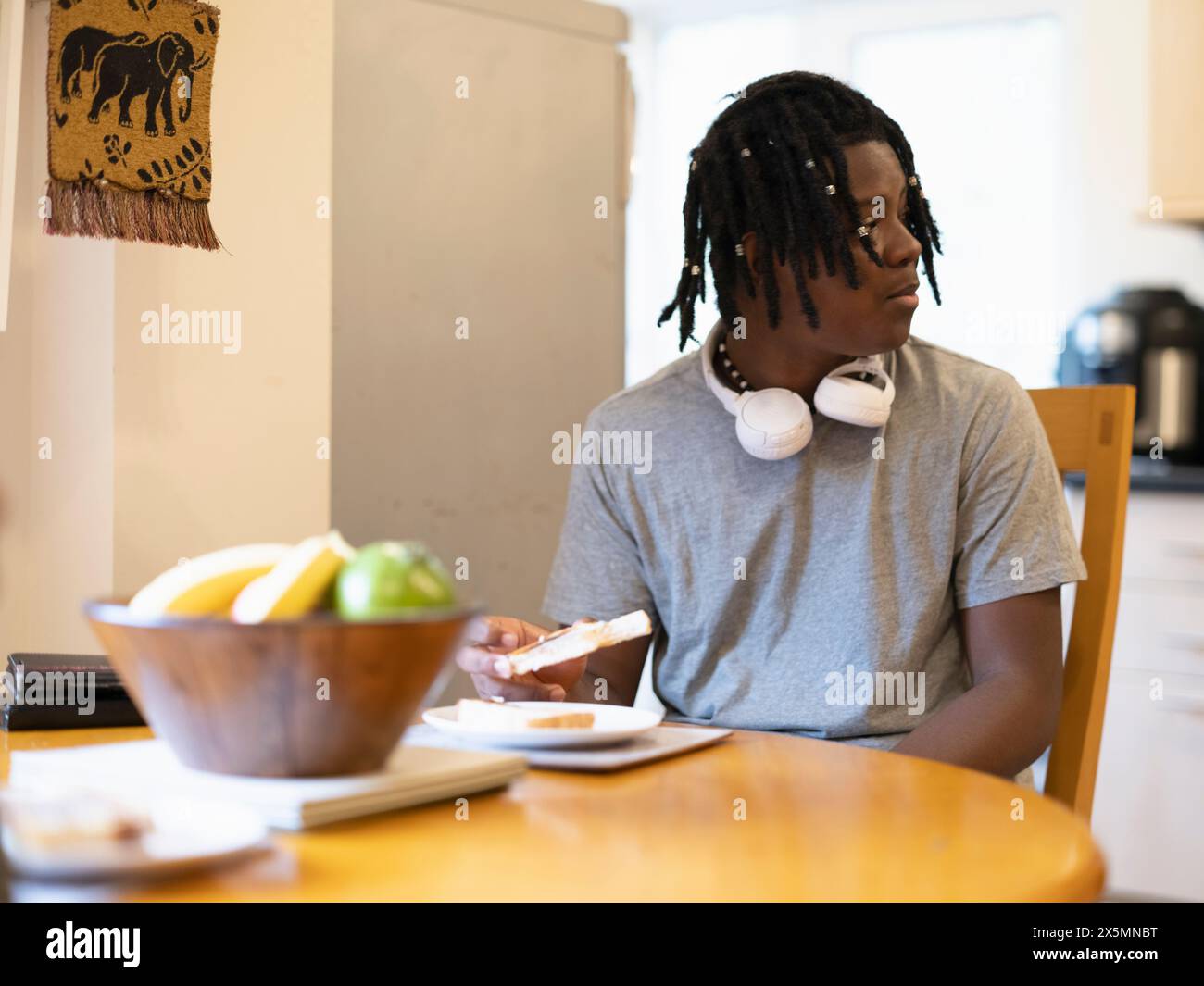 Teenage boy eating toast at table Stock Photo - Alamy